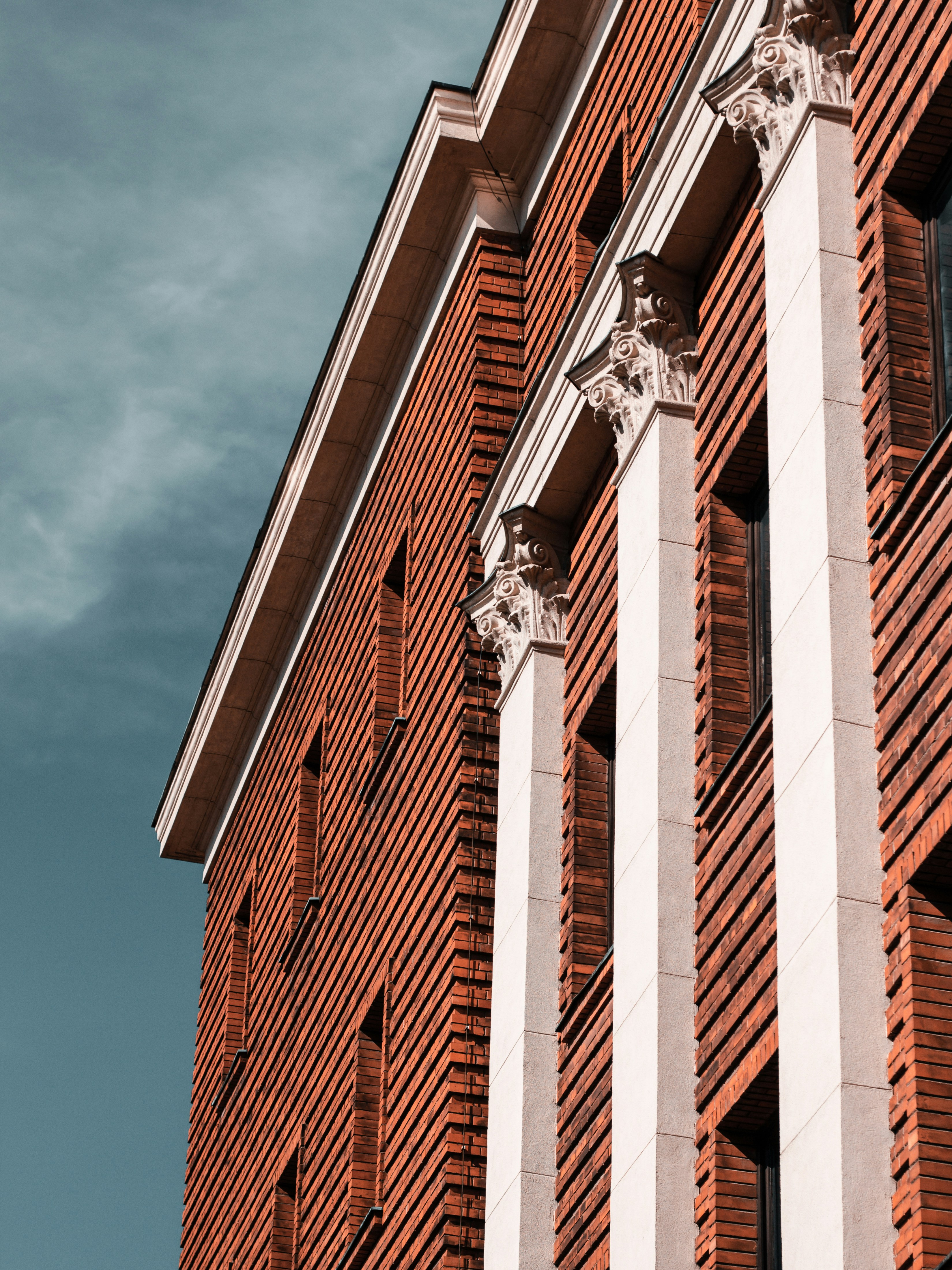 A tall red brick building with white columns photo – Free Unsplash ...