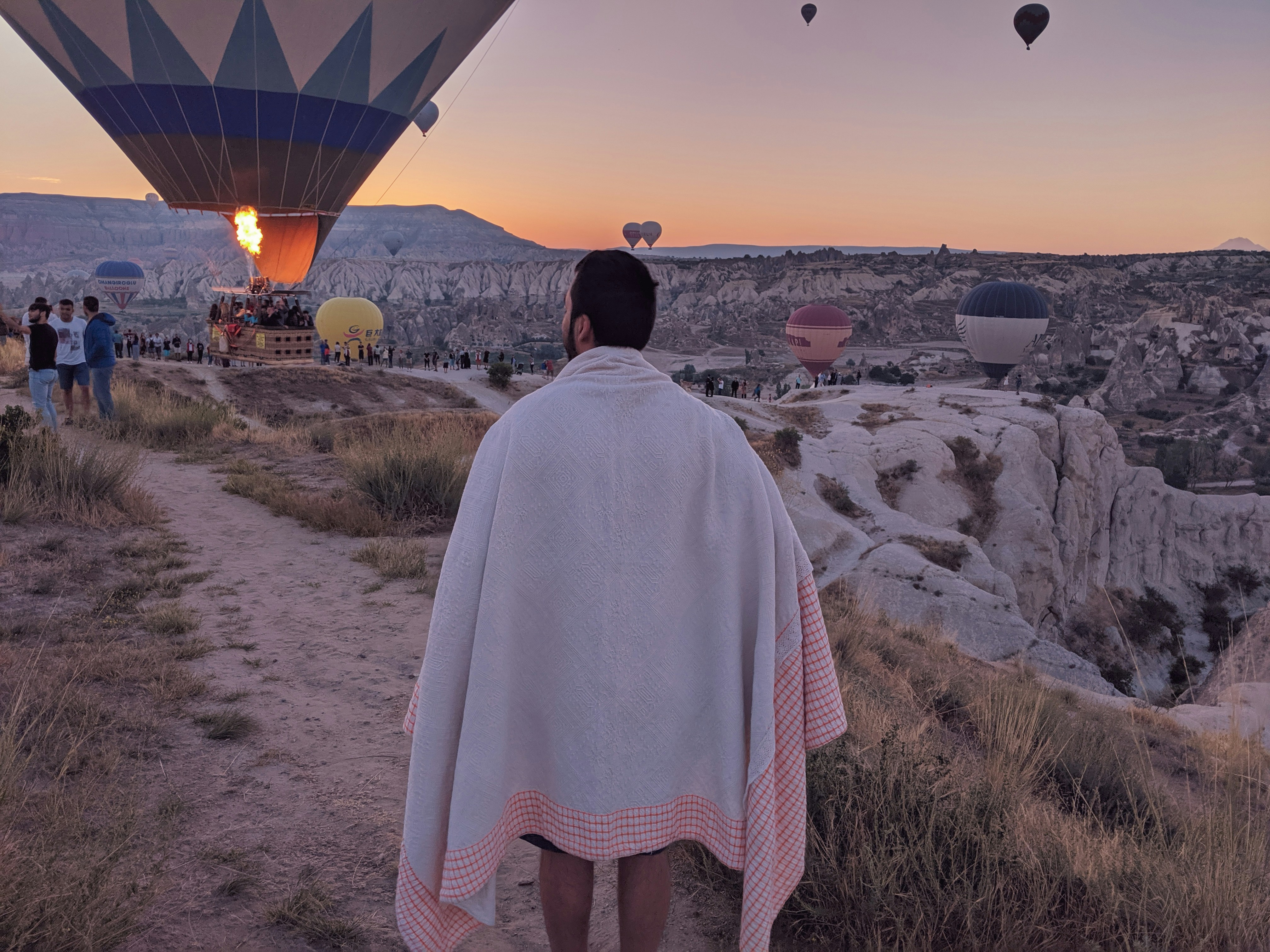 Wrapped in Light: A Lone Traveler Amid Soaring Balloons at Dusk