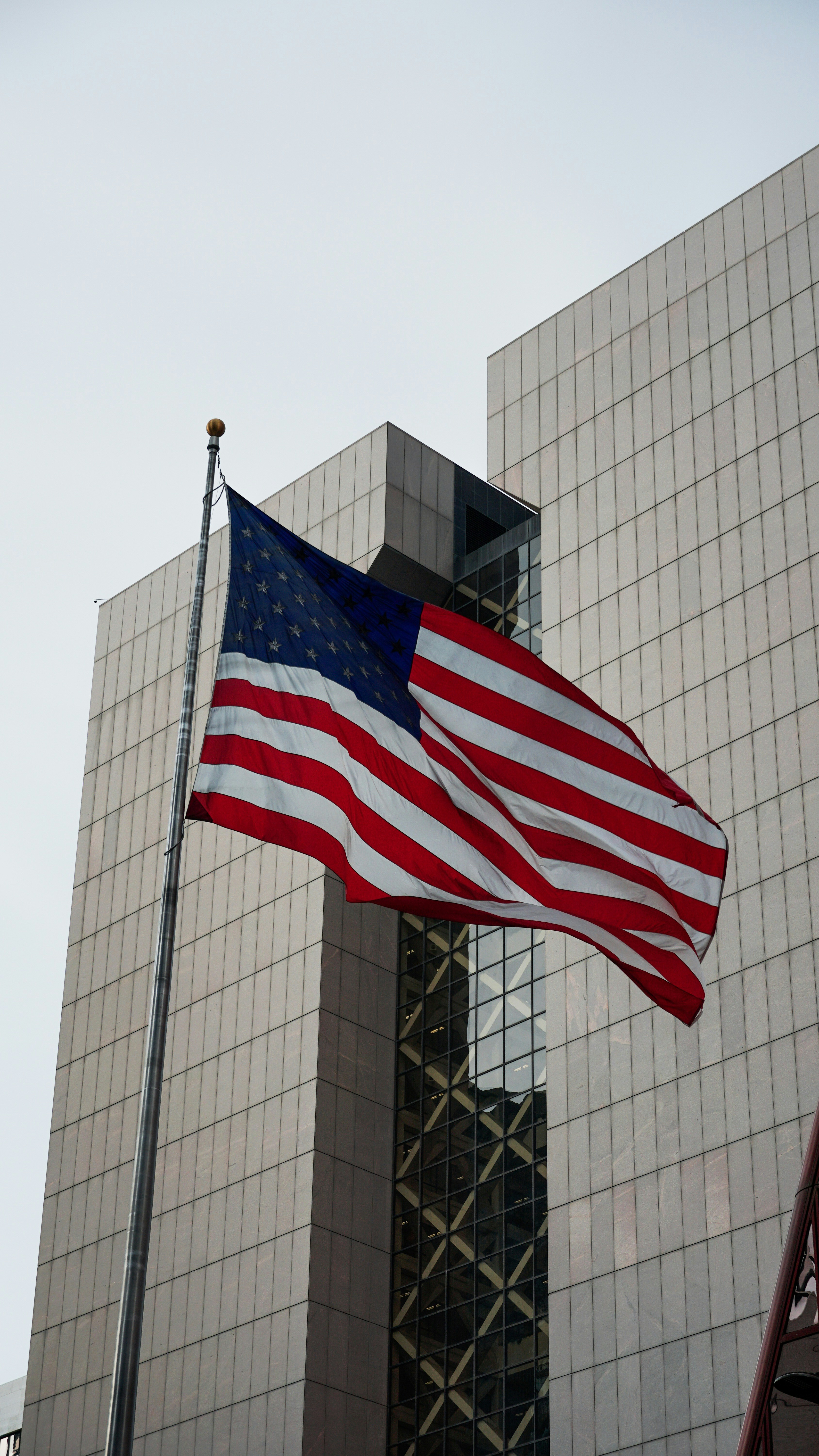 American flag billowing in the wind, set against a backdrop of contemporary architecture.