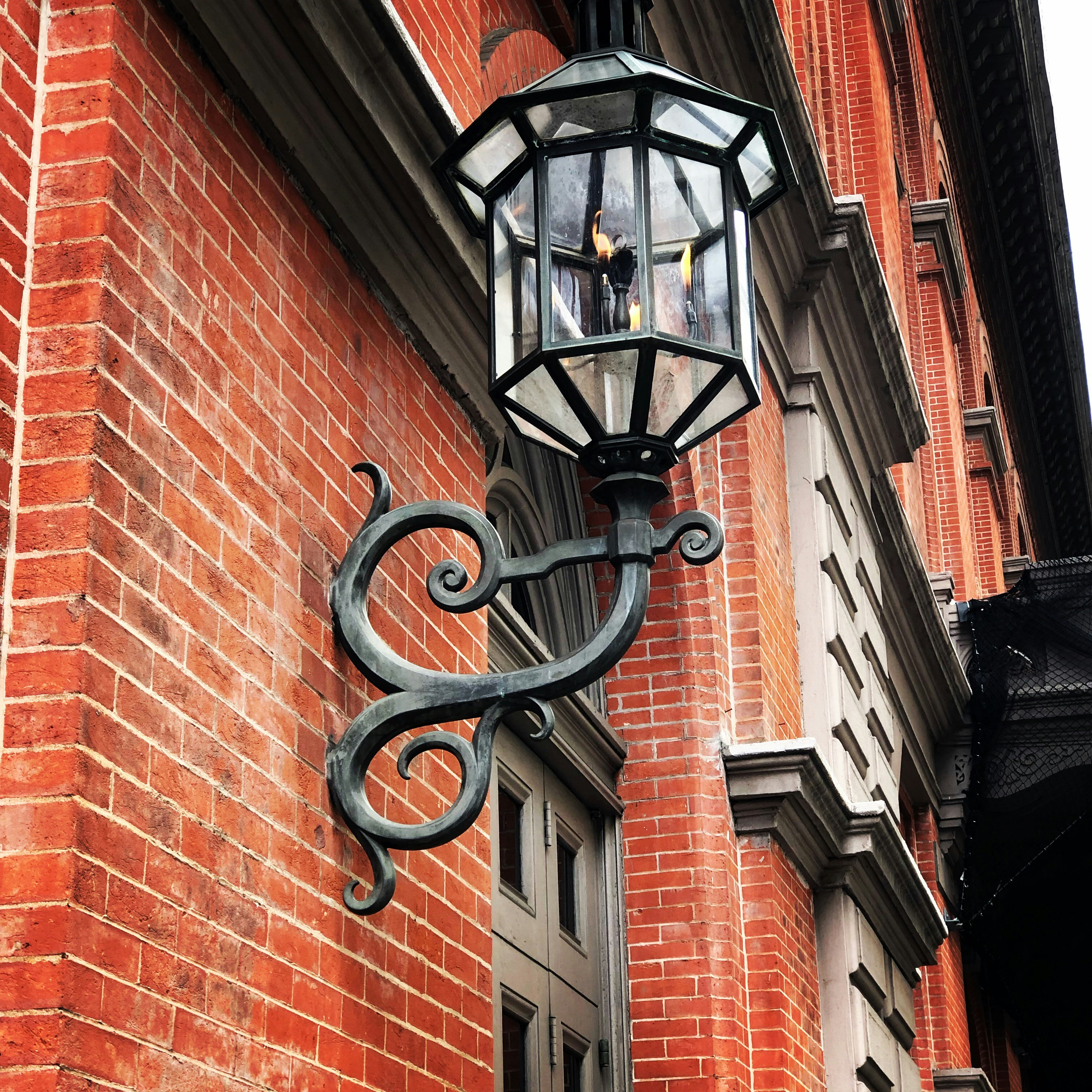 Lantern with Curved Iron Brackets Against Red Brick Facade