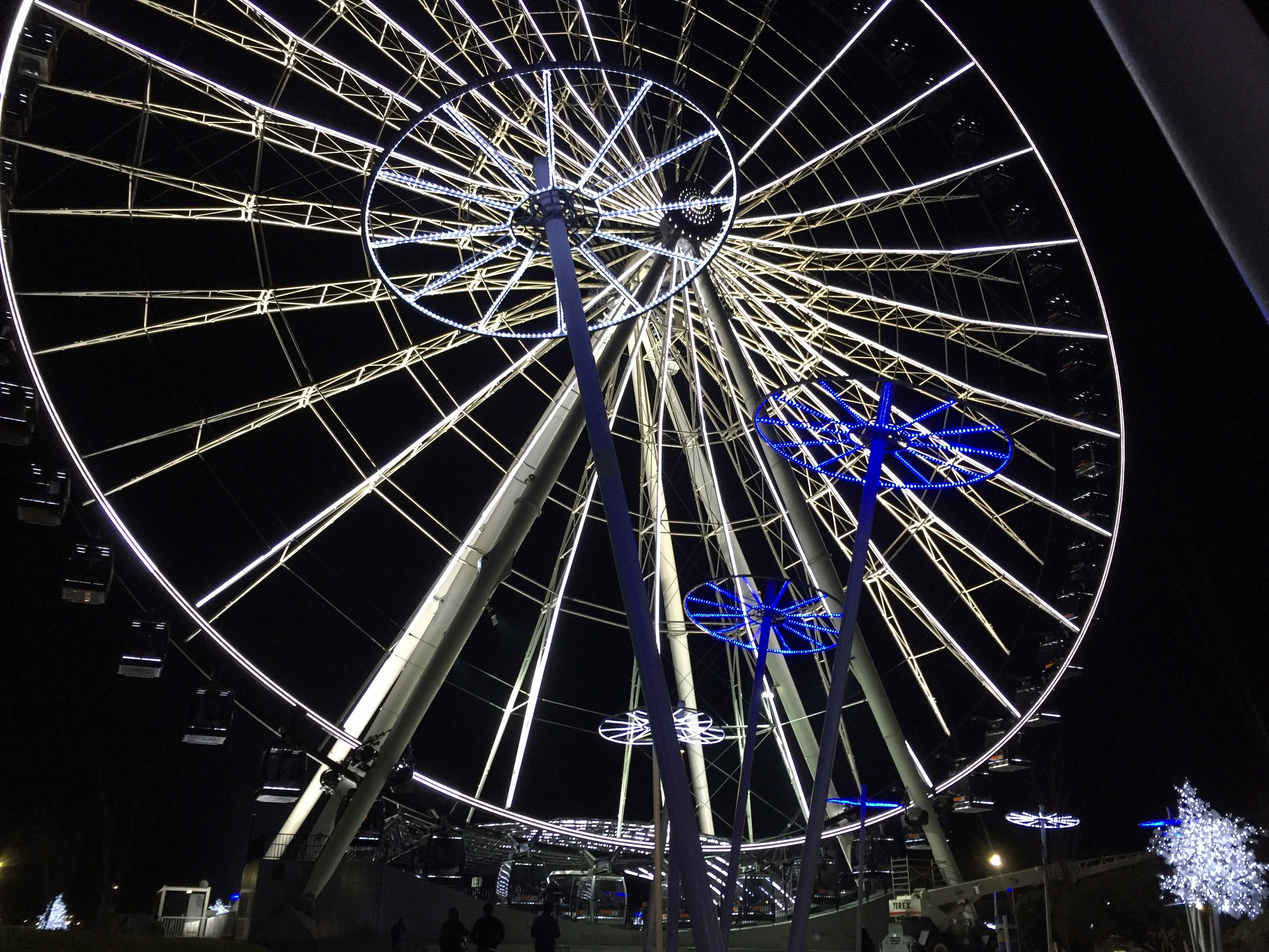 Illuminated Ferris wheel towering against the night sky, showcasing intricate light patterns.