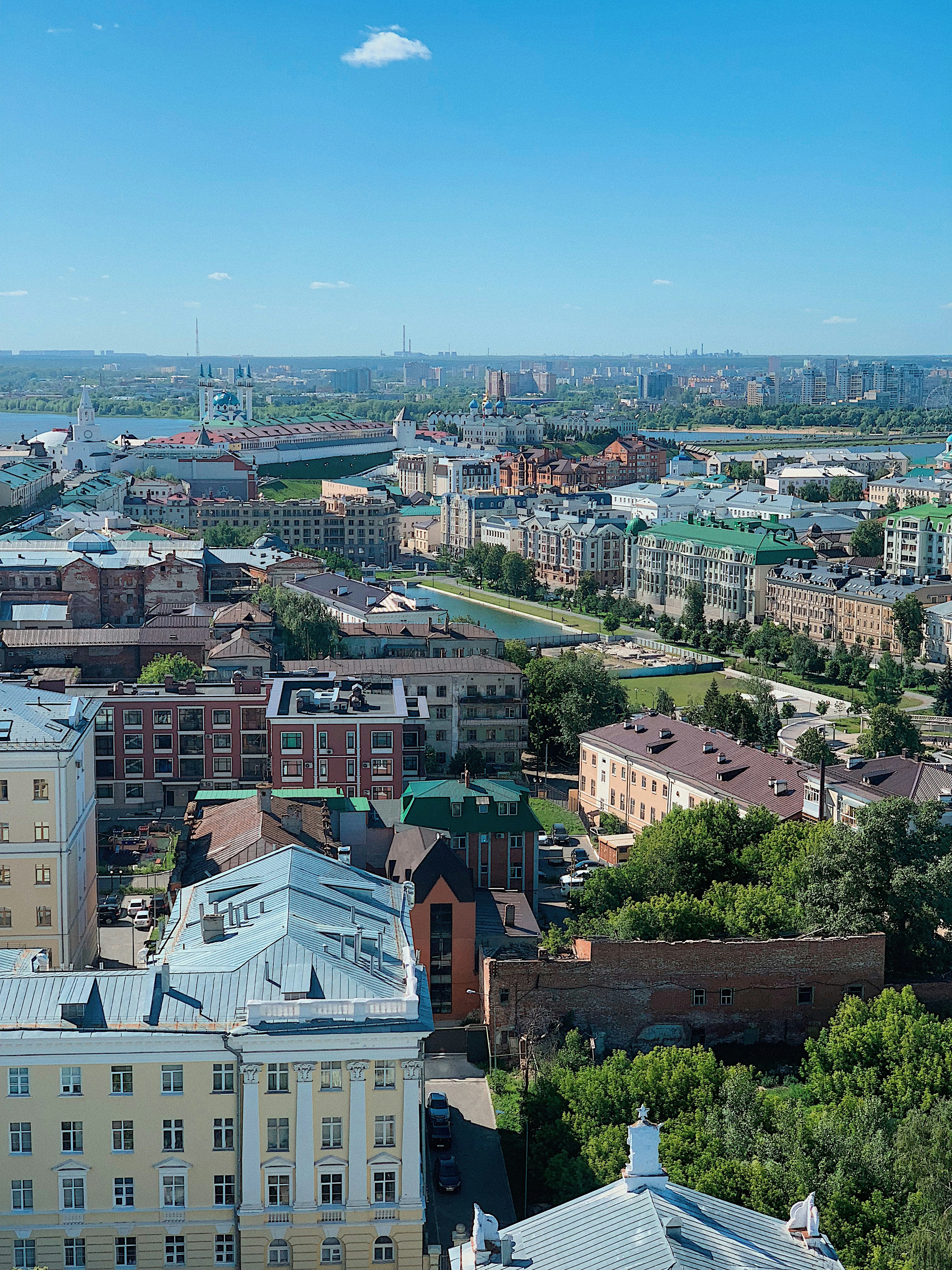 A panoramic view of a vibrant city, showcasing a mix of modern and historical architecture along a river. Lush greenery complements the urban landscape.