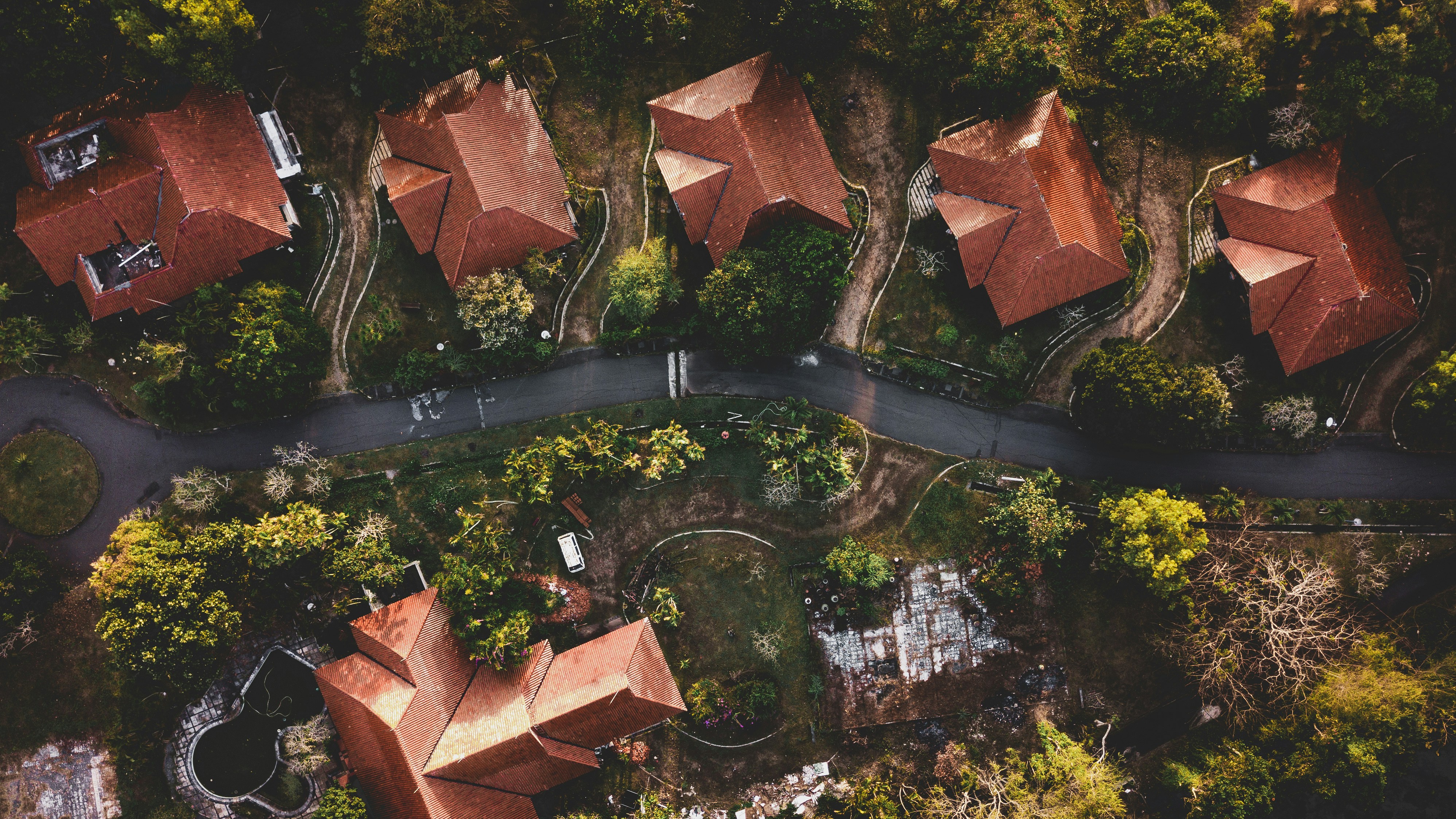Aerial view of a suburban neighborhood showcasing neatly arranged houses surrounded by lush greenery and winding roads.