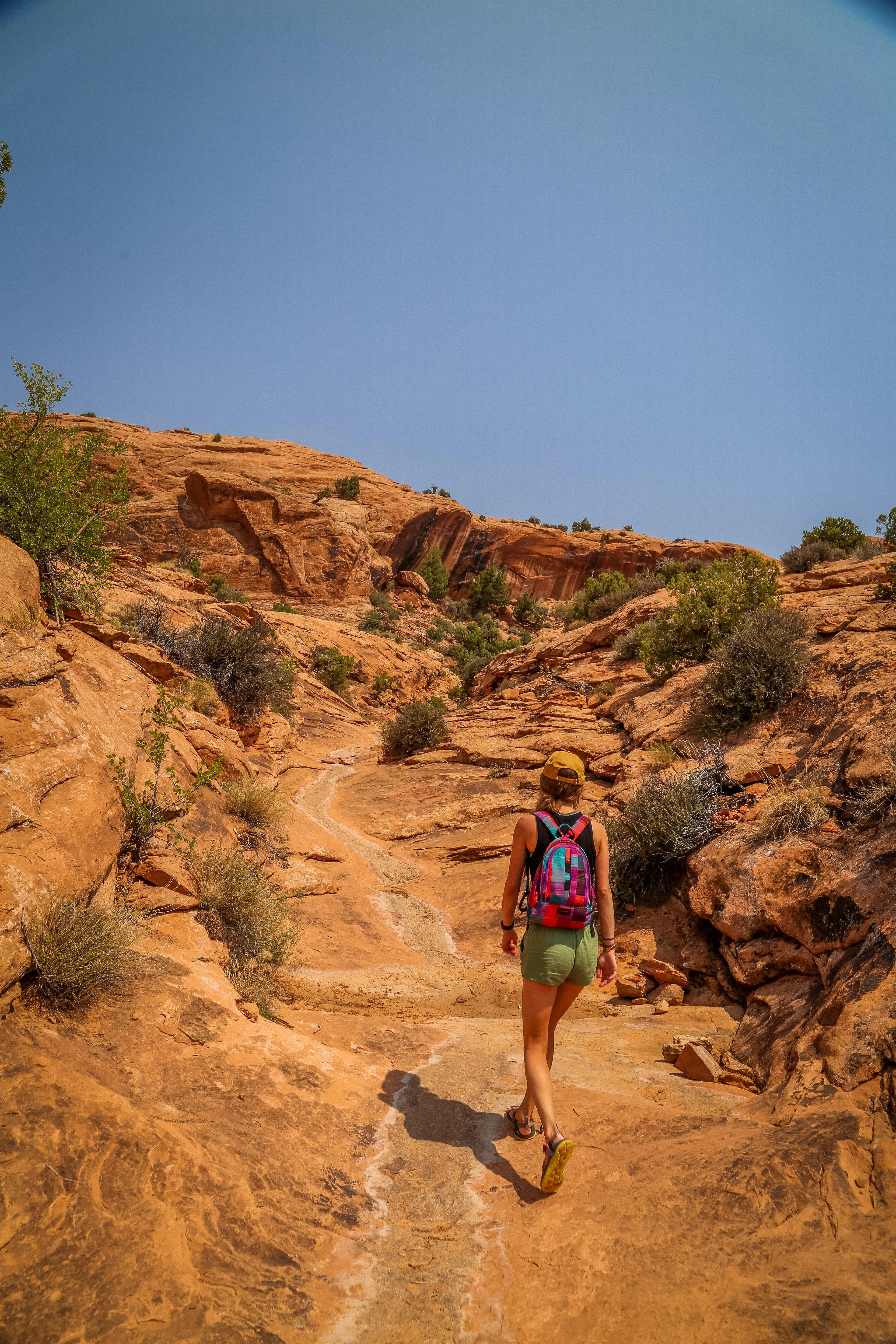 Rust-Red Ridge: A Lone Hiker Climbing the Sunlit Desert Corridor