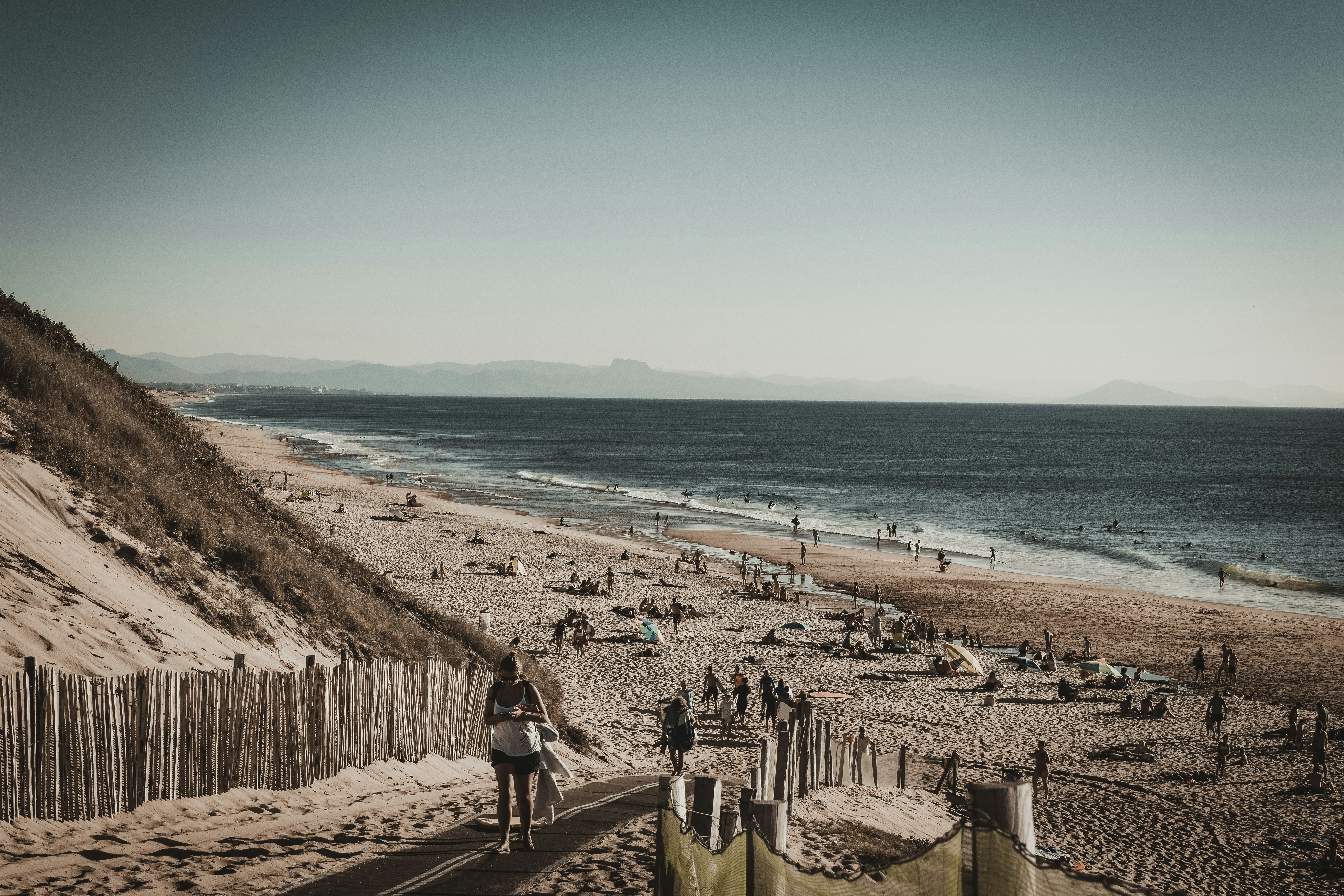 Dune Path to the Busy Shoreline: A Sunlit Beachfront Moment