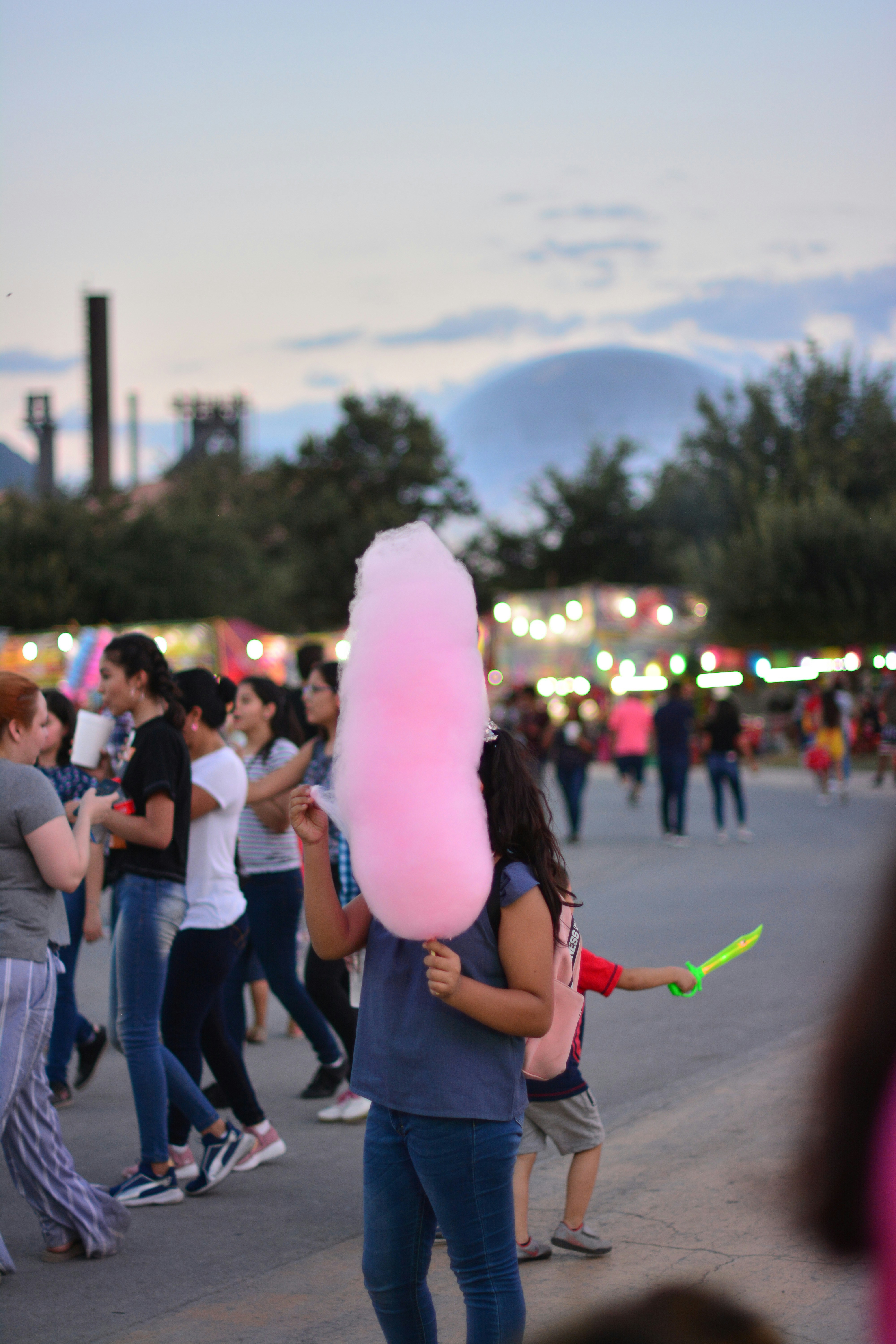 Candy Cloud at Dusk: Pink Cotton Candy Amid a Lively Street Fair