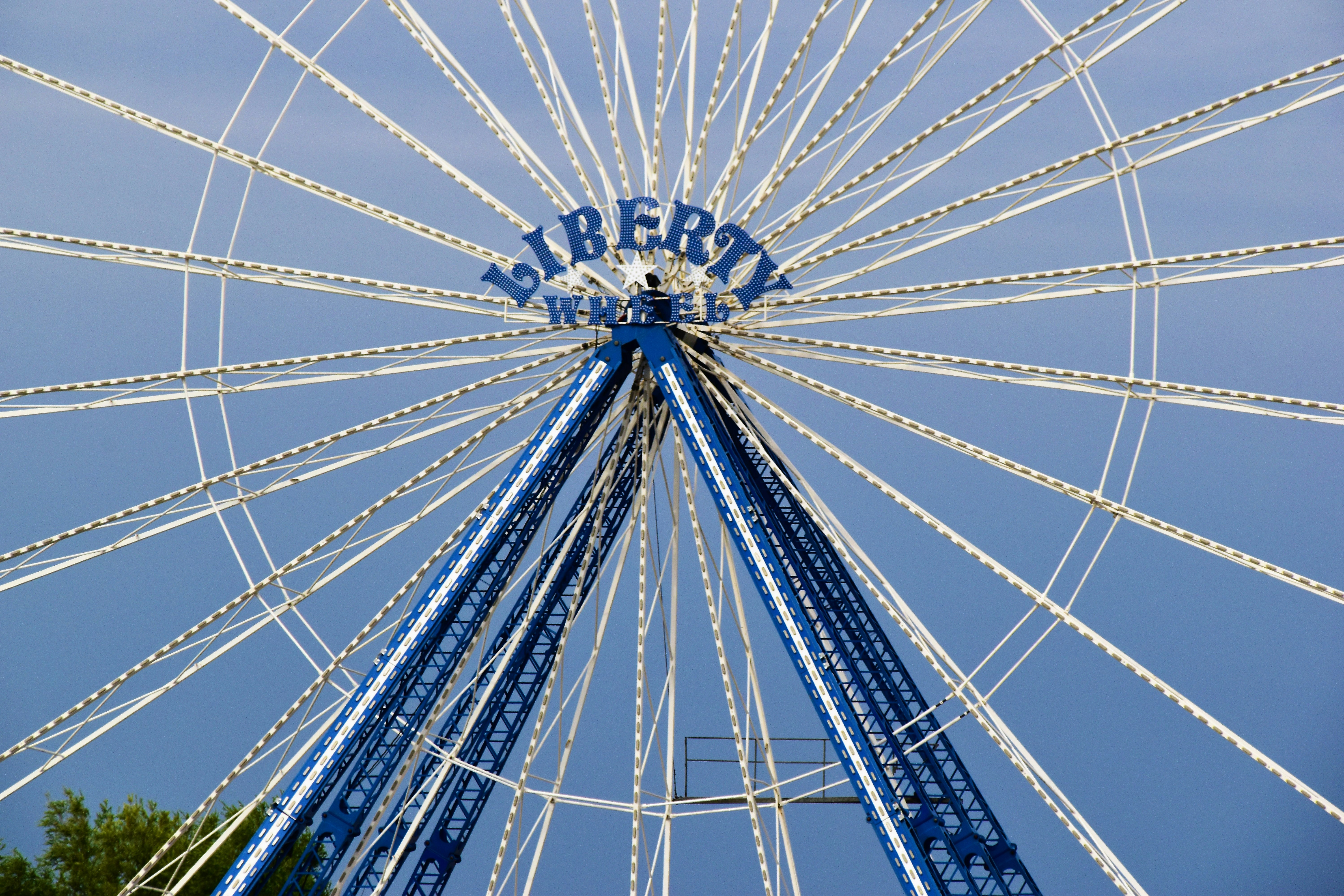 A striking Ferris wheel named 'Liberty' stands tall against a clear blue sky, showcasing its intricate support structure and vibrant colors.