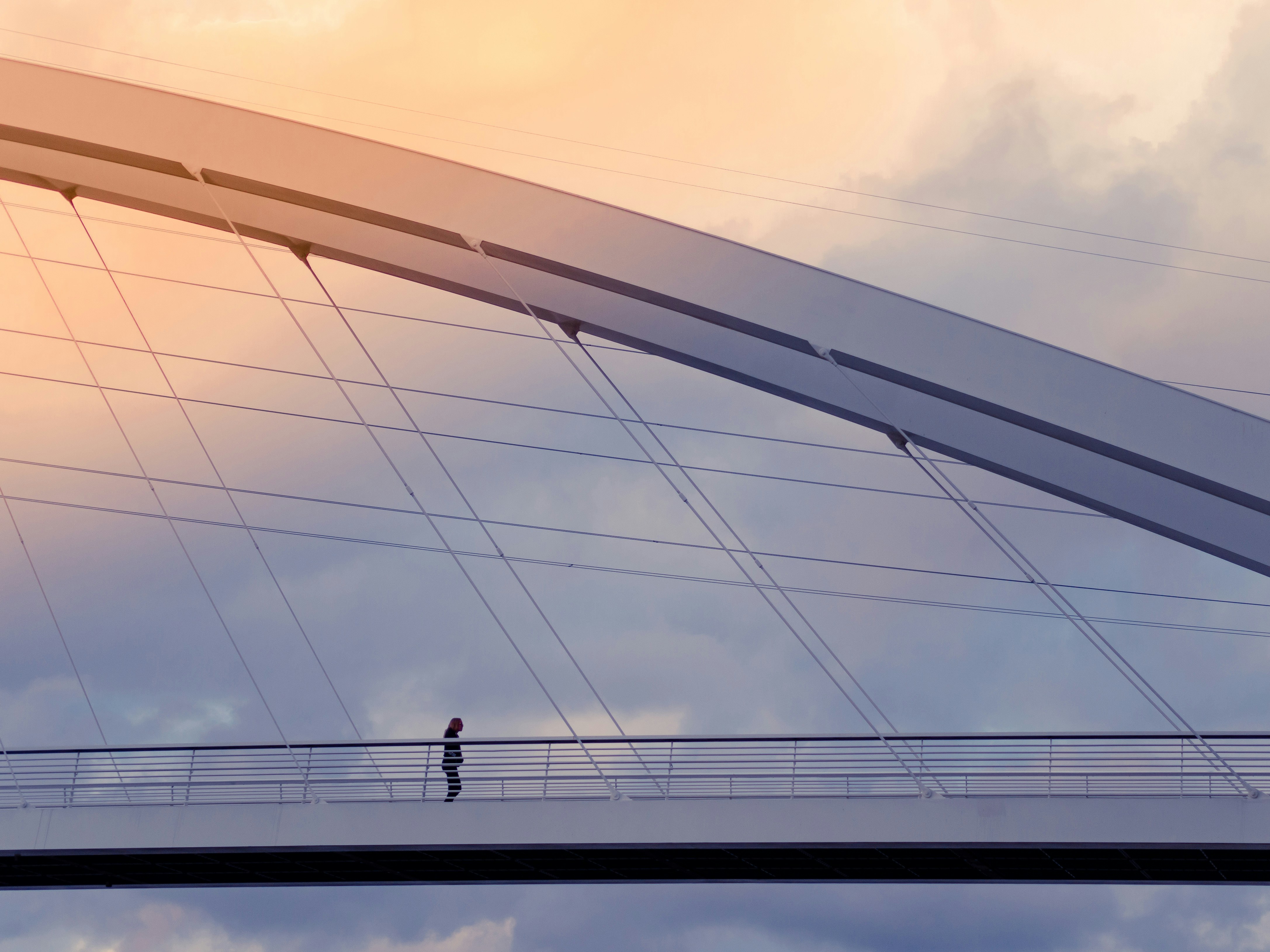 Lone pedestrian on a sun-kissed cable-stayed bridge at golden hour