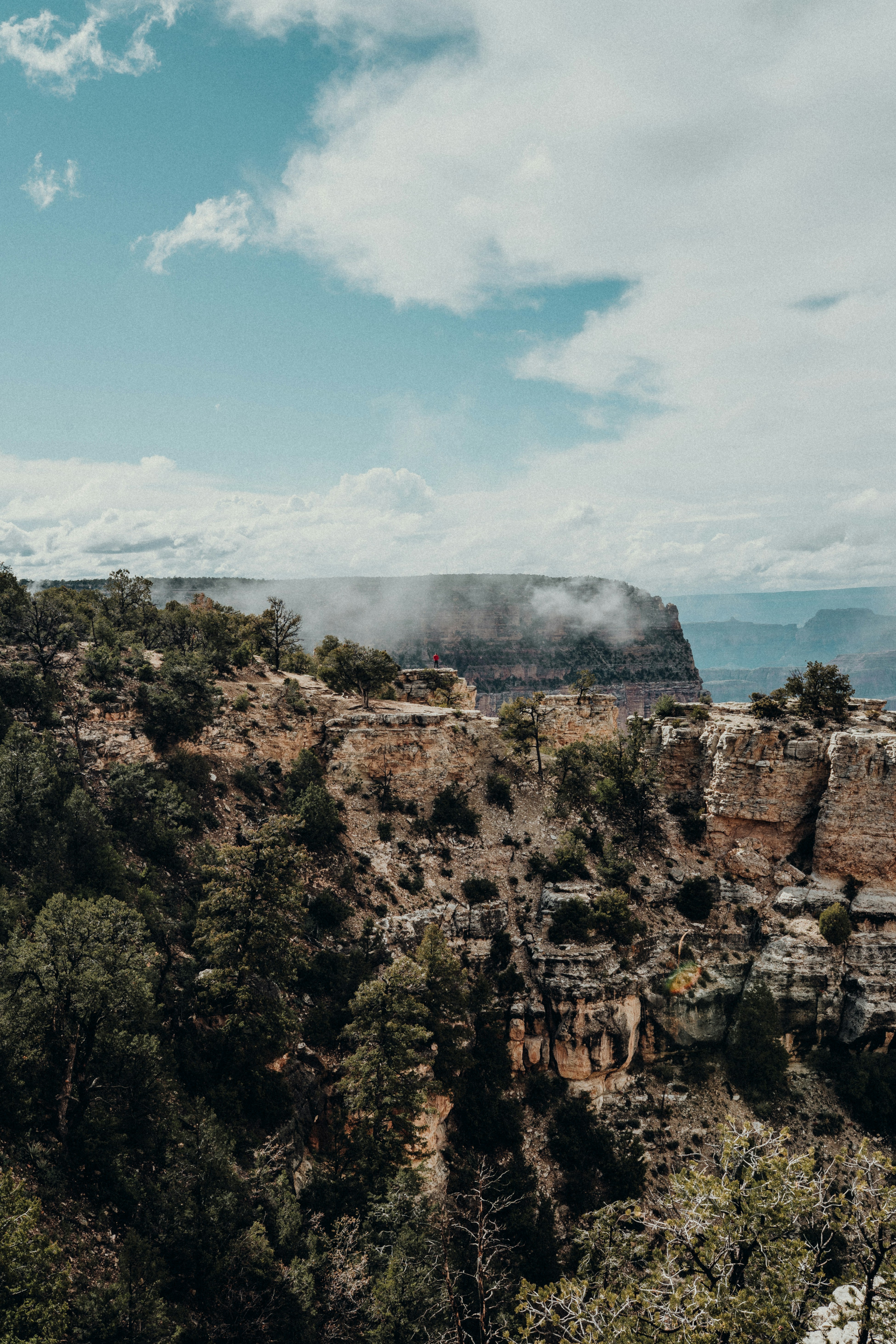 Red Speck on the Mesa: Smoke Drifts Across a Layered Canyon Rim