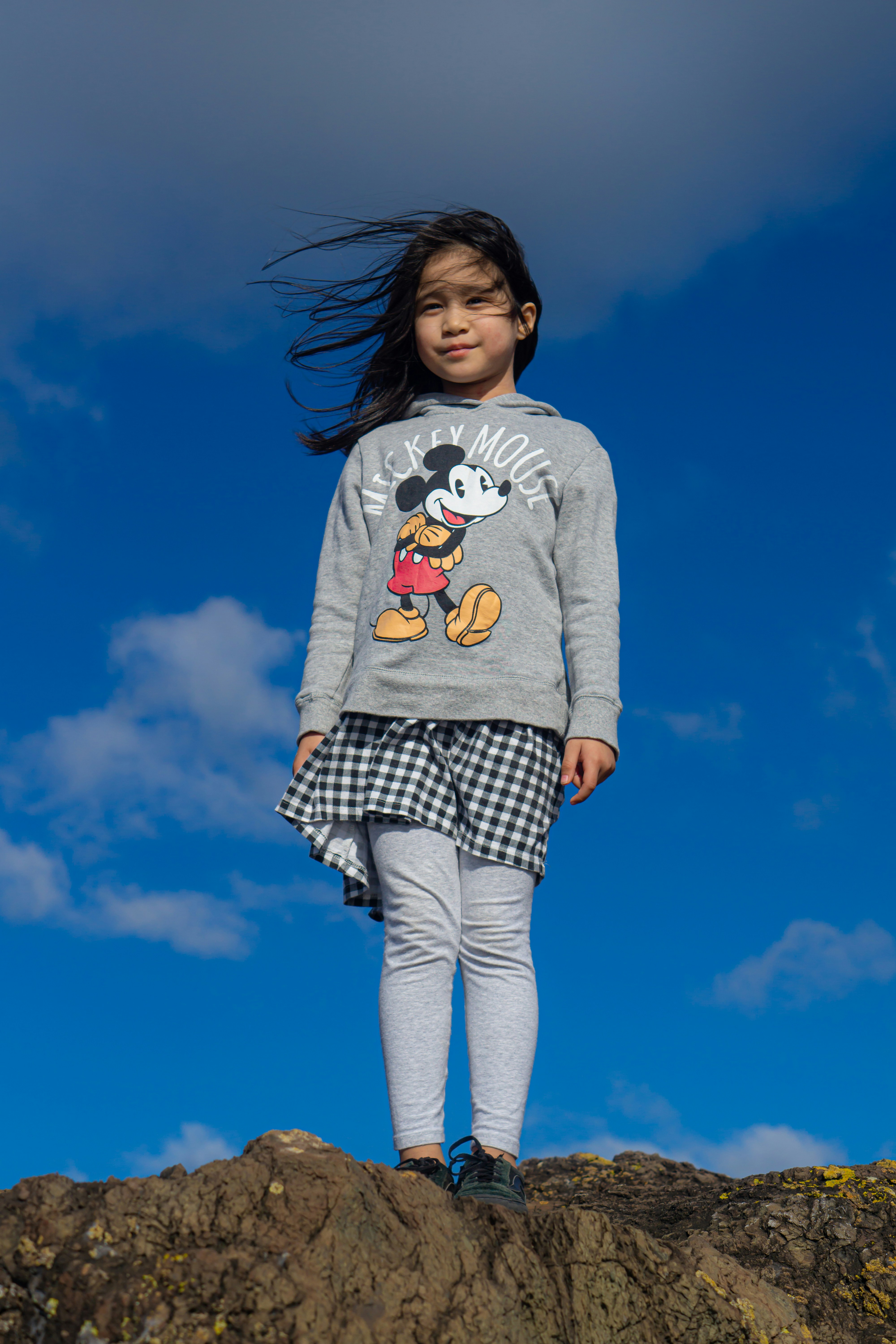 Keyboard on a Clifftop: A Girl in Mickey Sweatshirt Reaches for the Sky