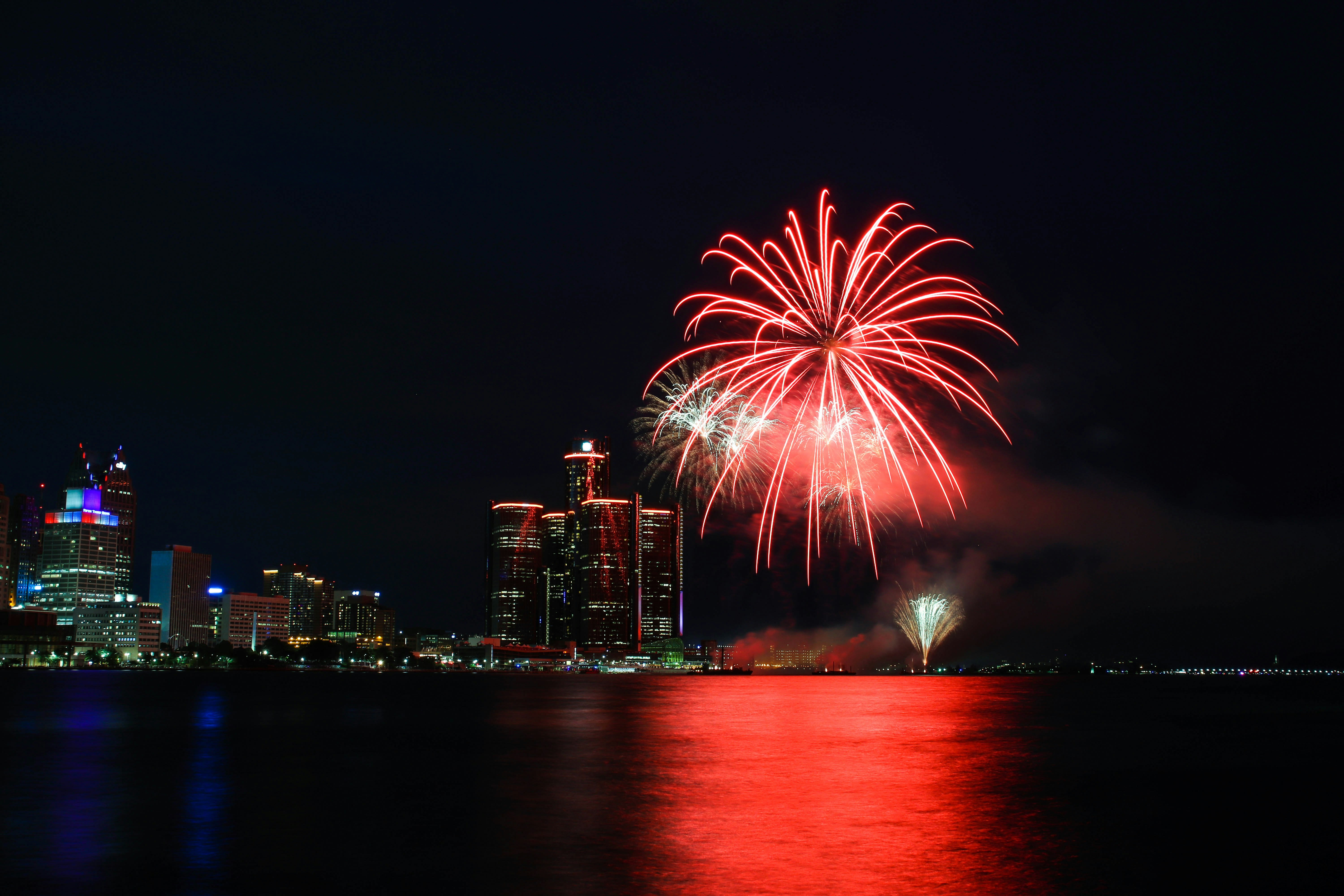 Red fireworks display above city buildings during night photo – Free ...
