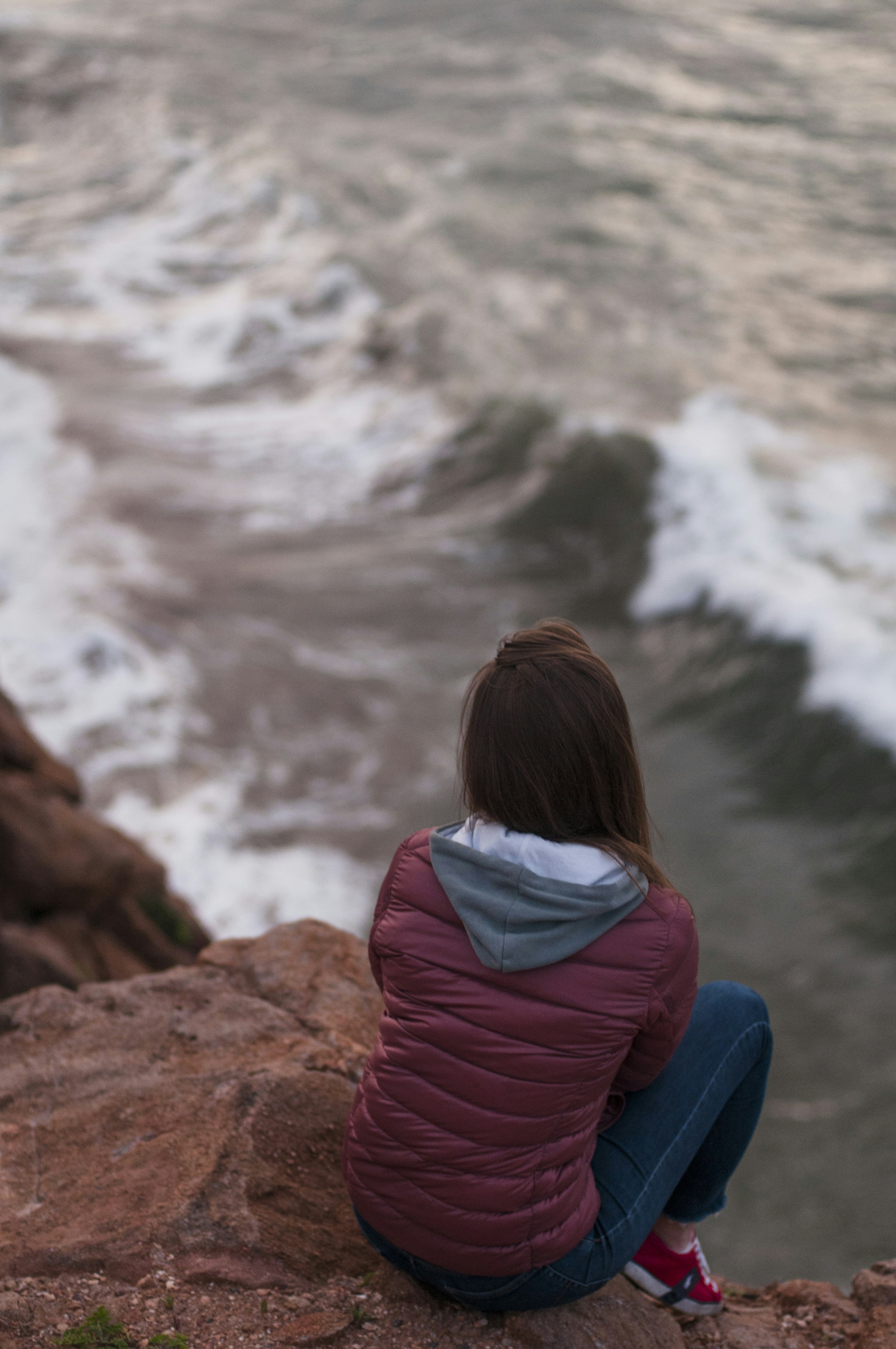 Woman sitting on rock at the edge of island during day photo – Free ...