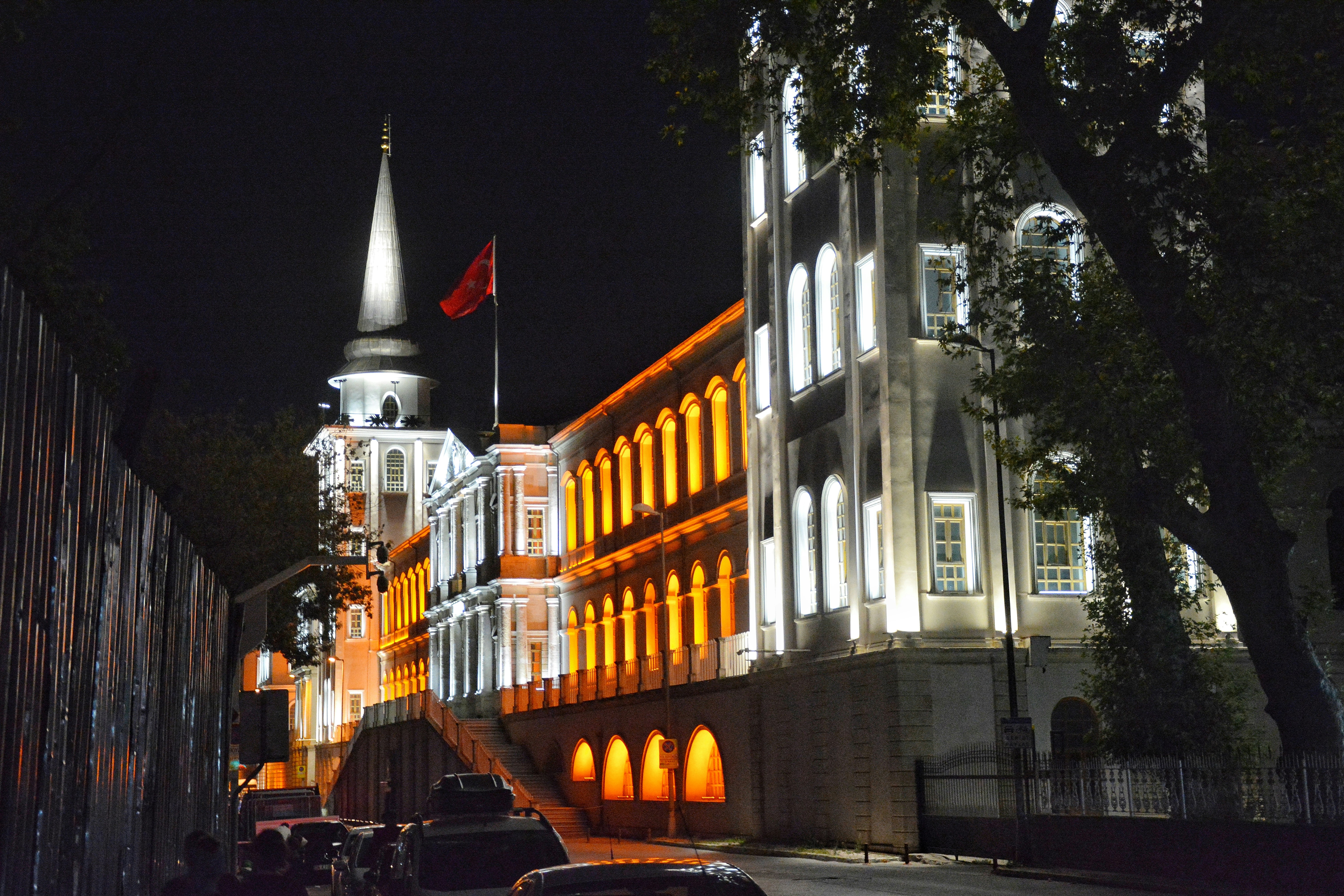 a city street at night with cars parked on the side of the road