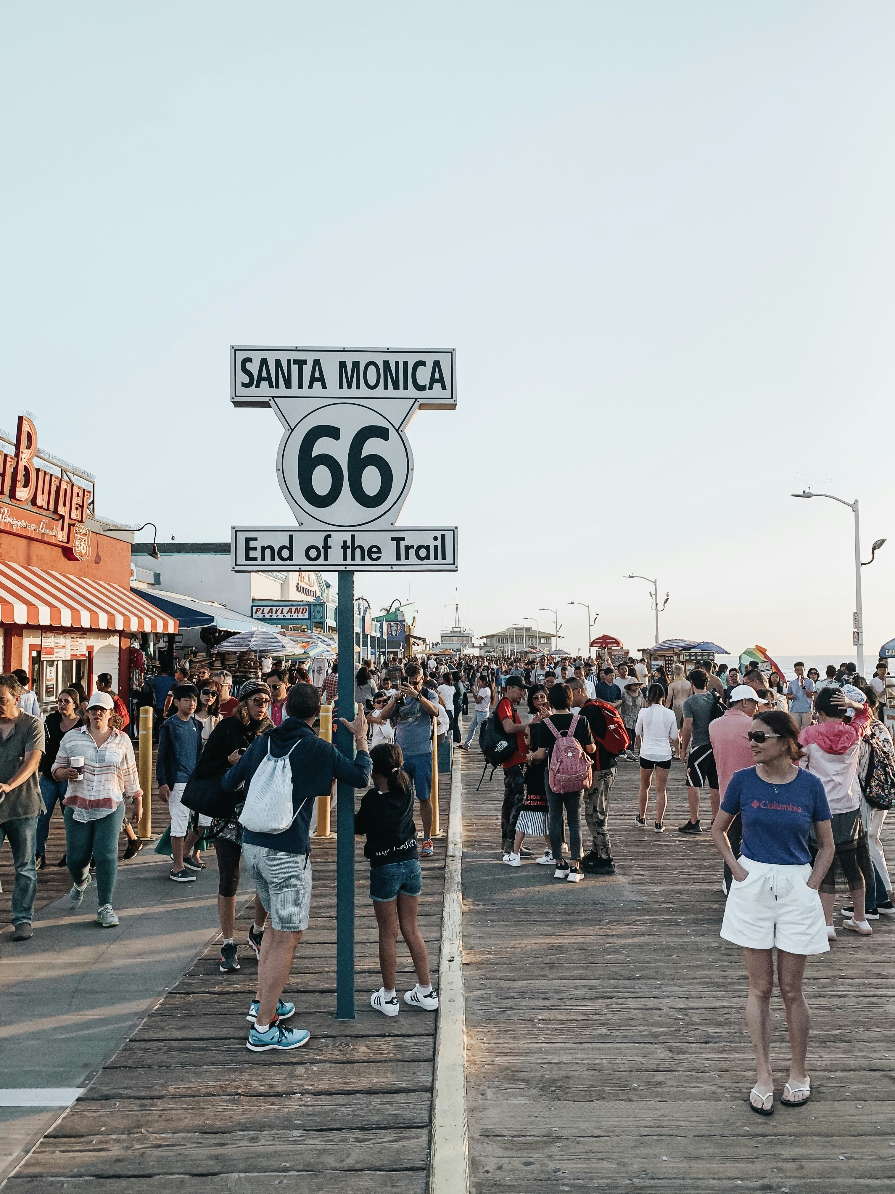 End of the Trail on a Sunny Santa Monica Pier: Route 66 Sign Dominates a Bustling Boardwalk