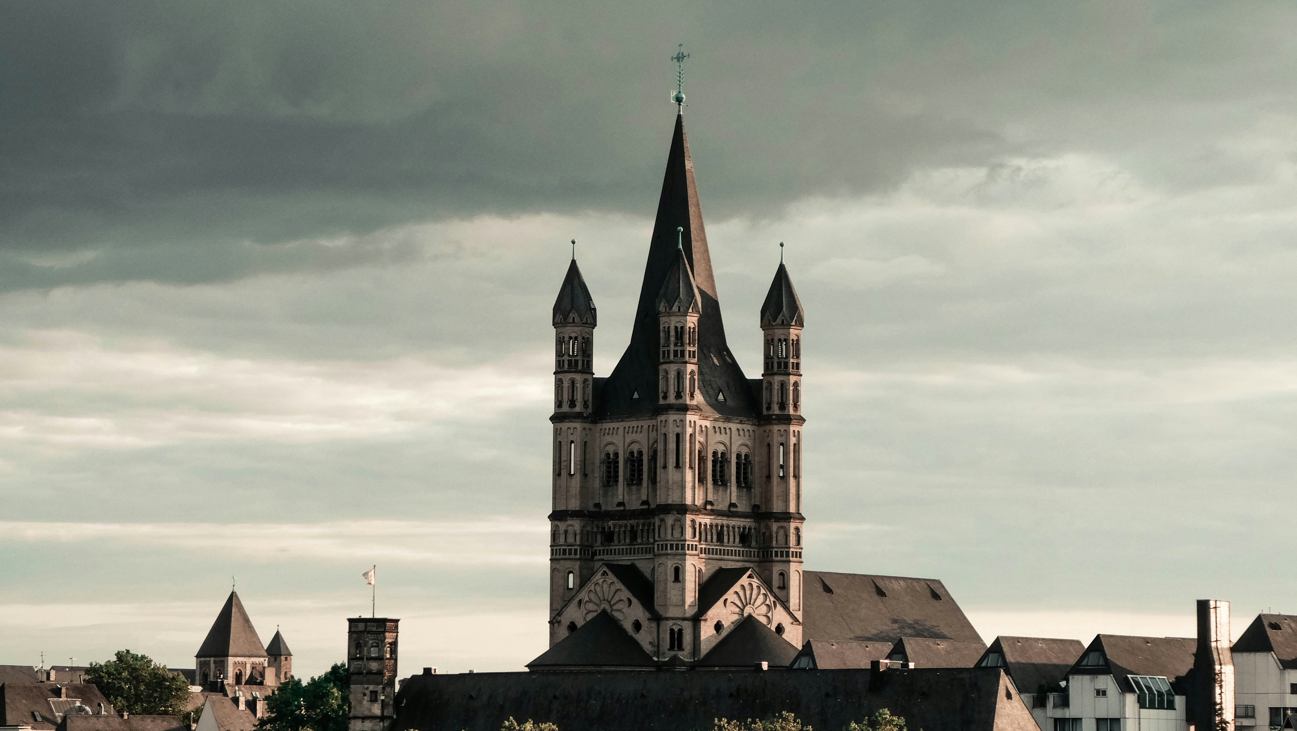 Gothic cathedral towers rise against a backdrop of moody clouds in Cologne.