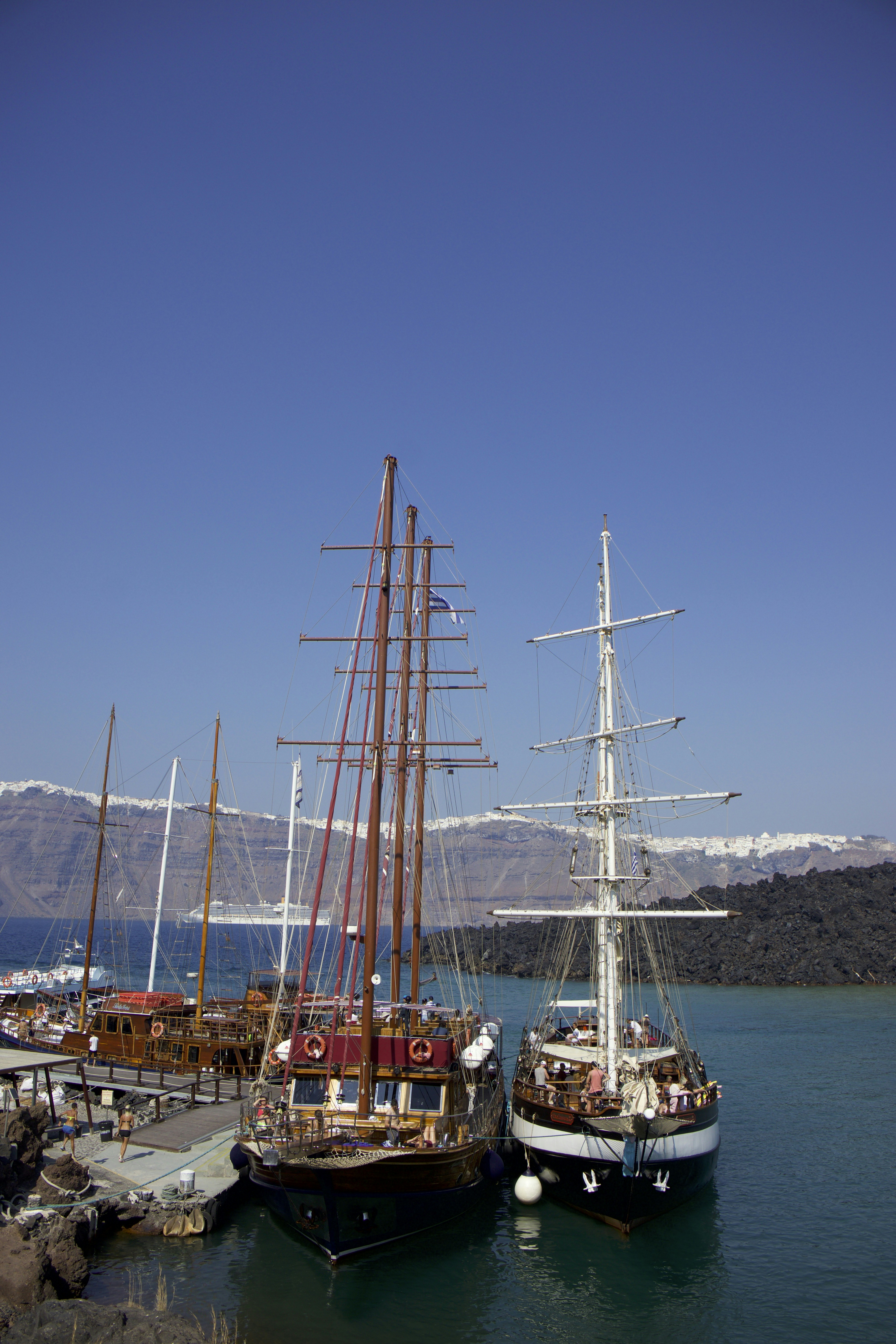 Twin Masts Over Turquoise Harbor at the Foot of Snow-Capped Peaks