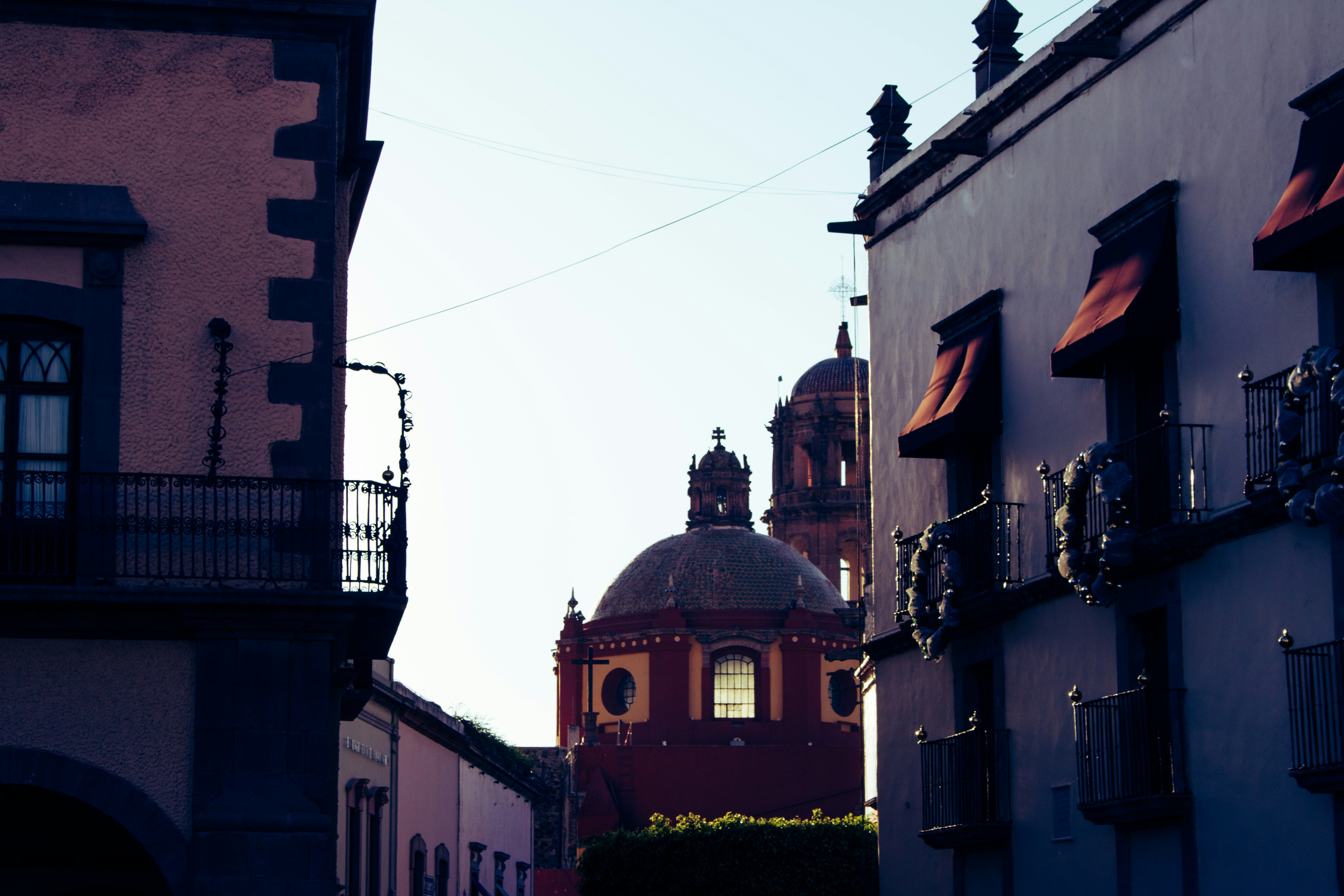 Historic buildings frame a vibrant dome peeking through the narrow street, showcasing architectural beauty and urban charm.