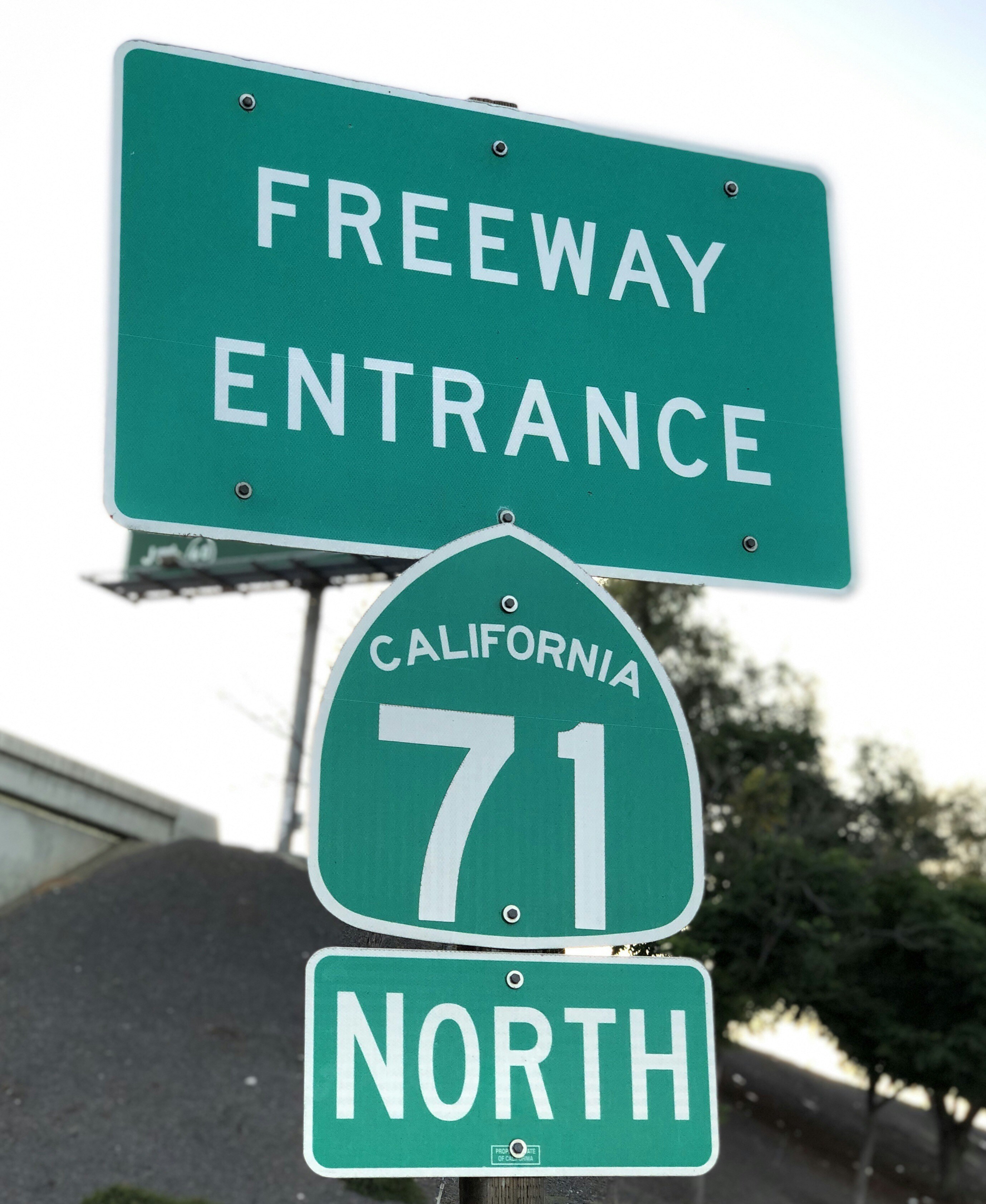 Green freeway entrance sign indicating California 71 North. The sign is prominently displayed against a blurred background.