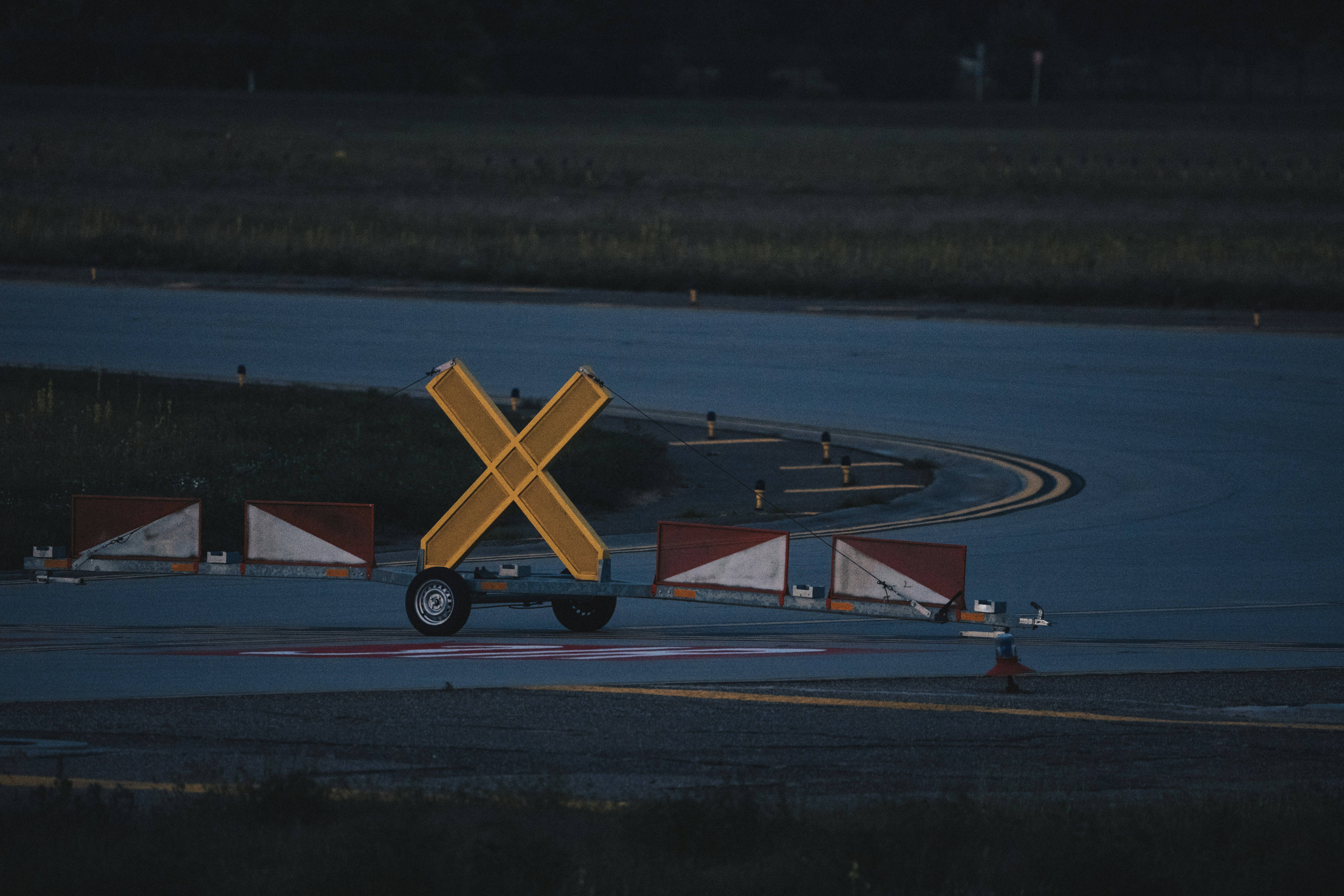 Dusk Runway Signal: The Yellow X on a Mobile Trailer at the Curve