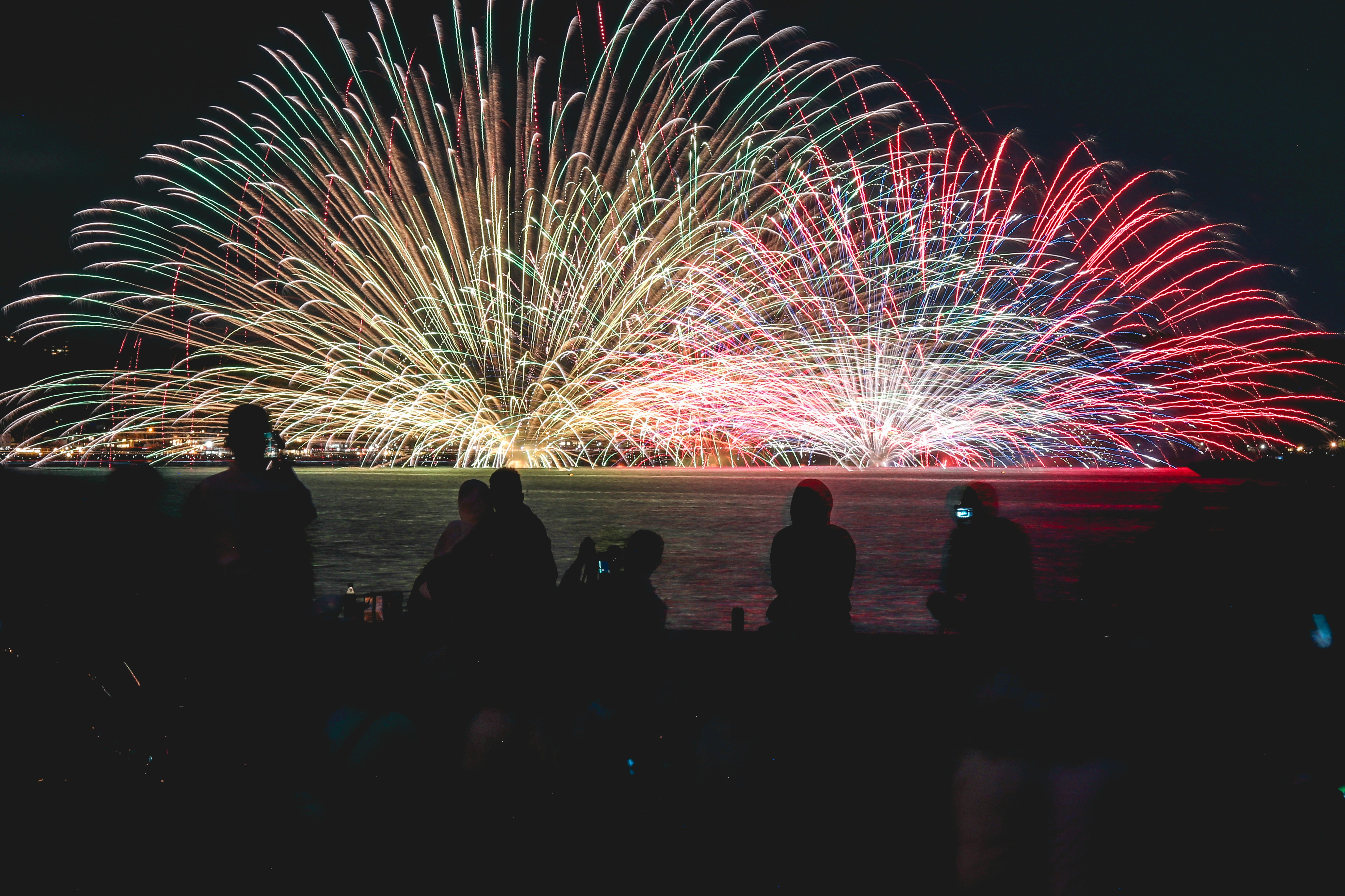 Midnight Cascade: Multicolored Fireworks Over the Quiet Bay