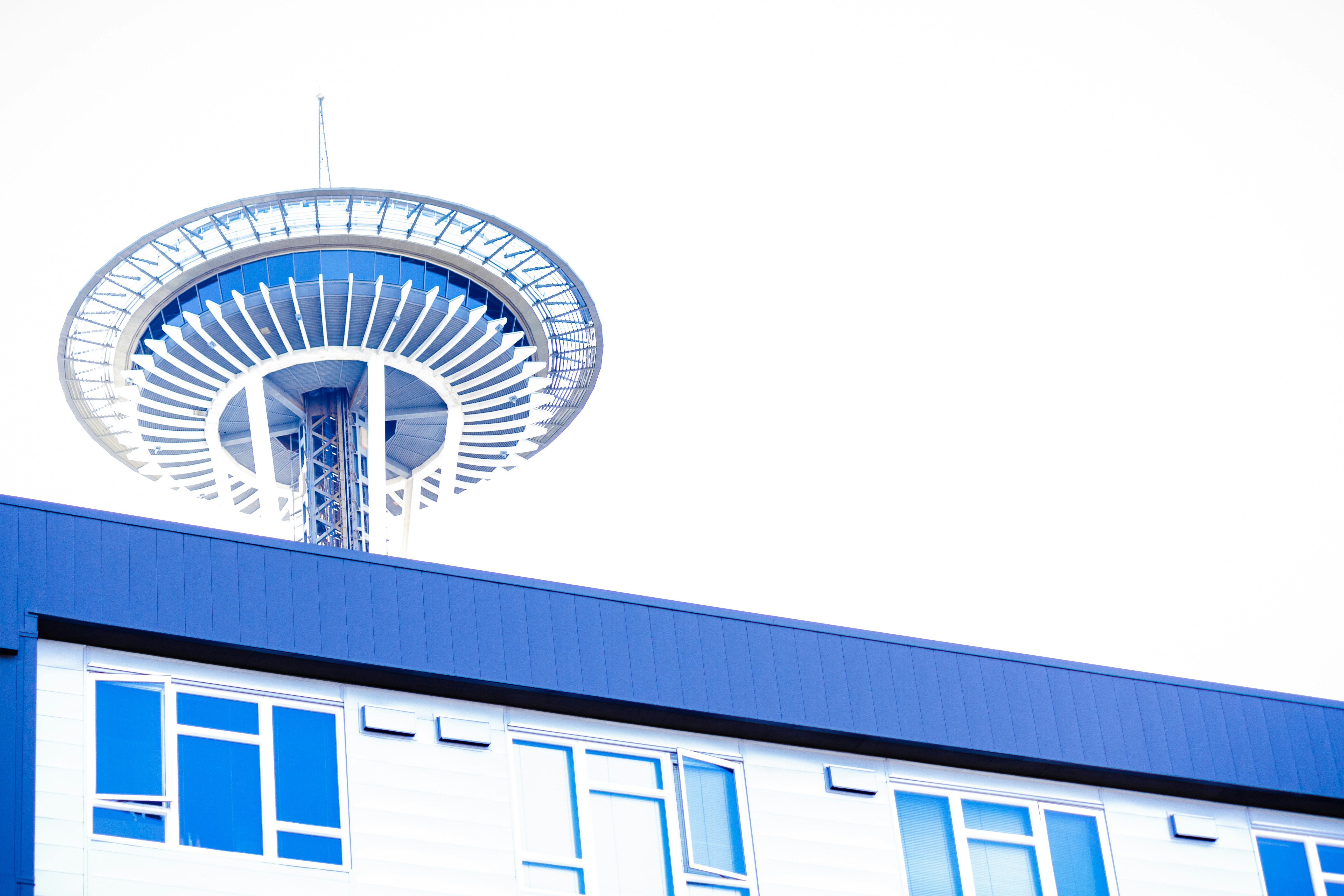 The iconic Space Needle rises above a contemporary building, showcasing a blend of urban design and engineering prowess.
