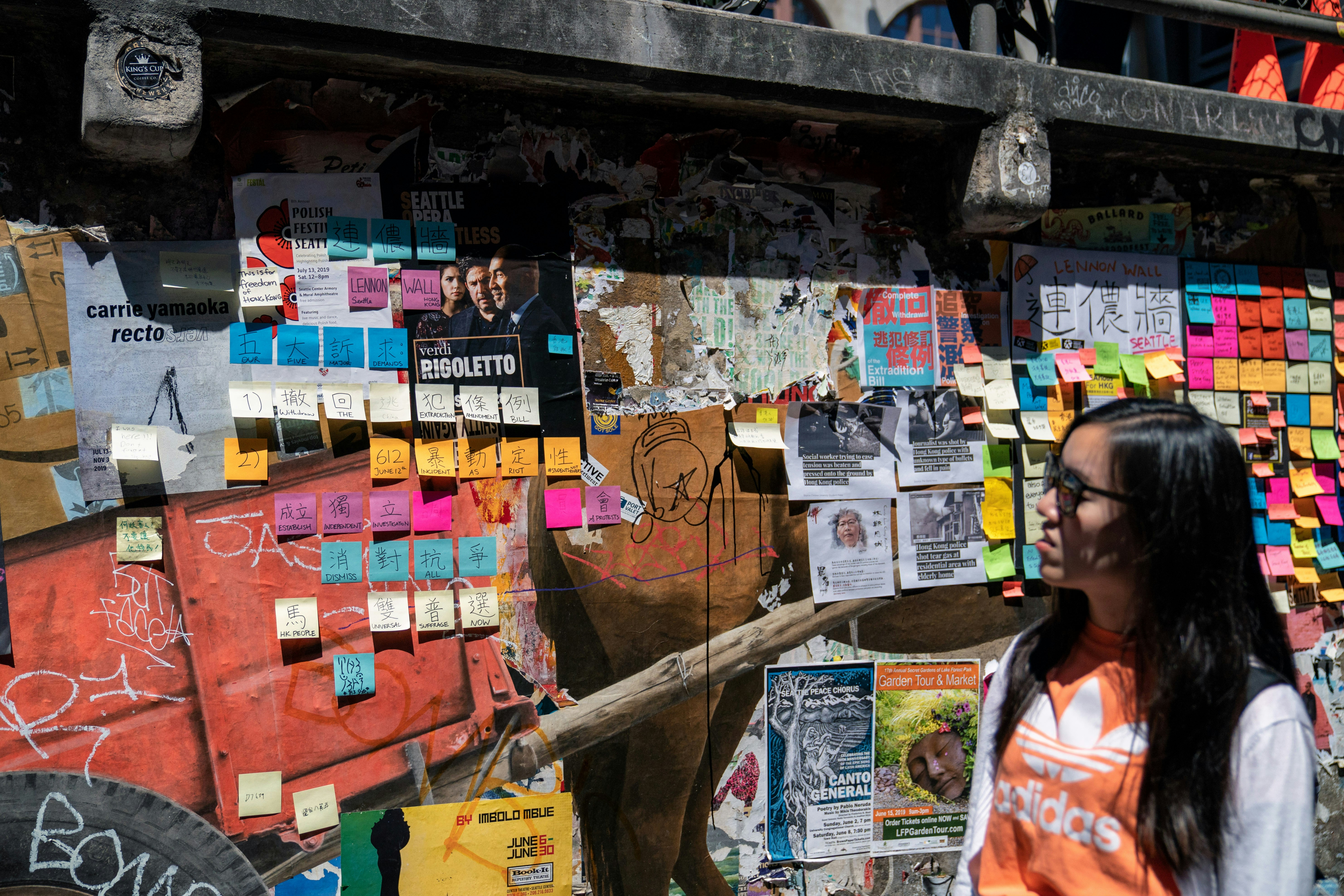 Post-it Portrait: A Woman in Orange Framed by a Wall of Flyers and Sticky Notes