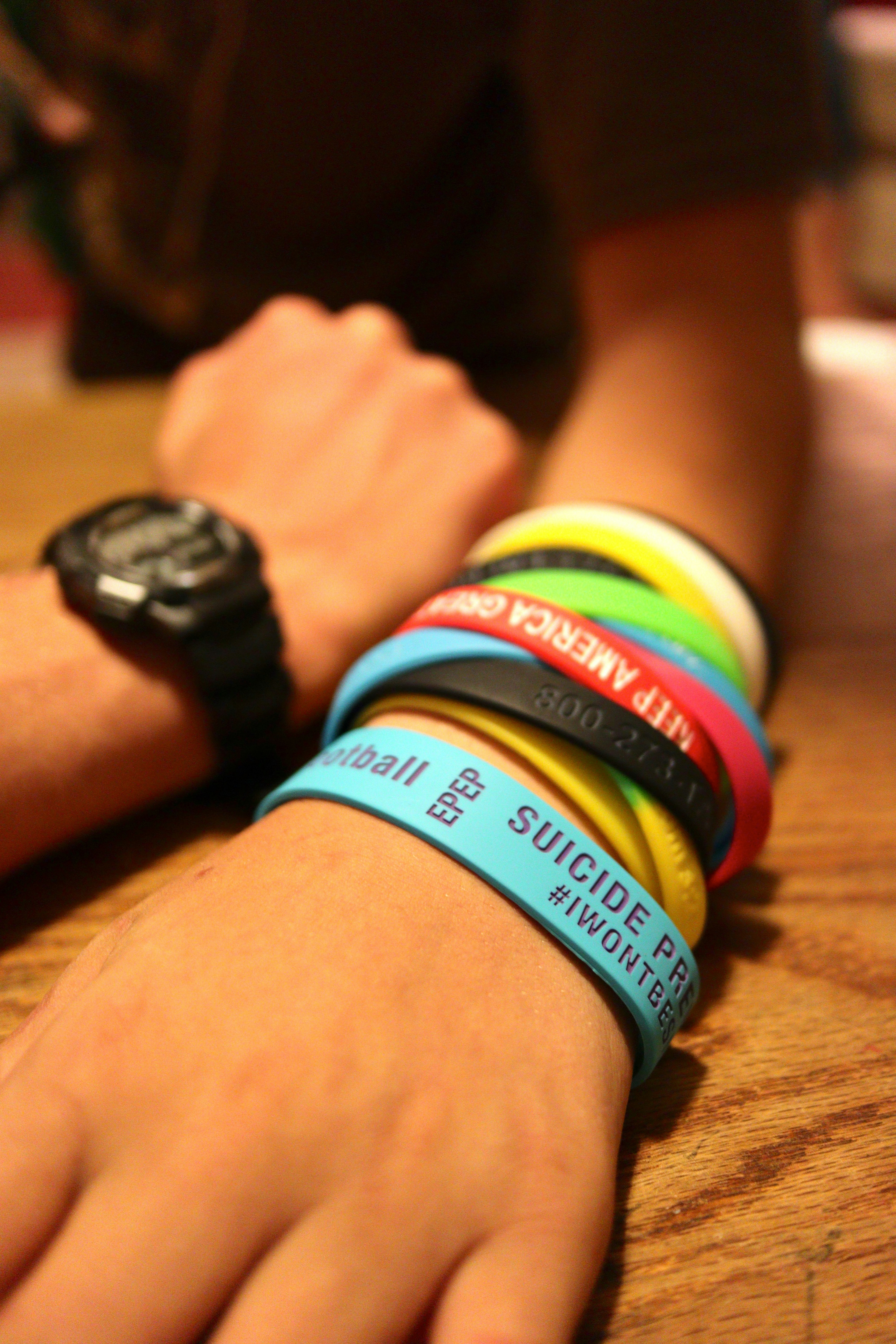 Colorful wristbands stacked on a wrist, symbolizing various causes and movements. A watch is also visible, adding to the personal touch.