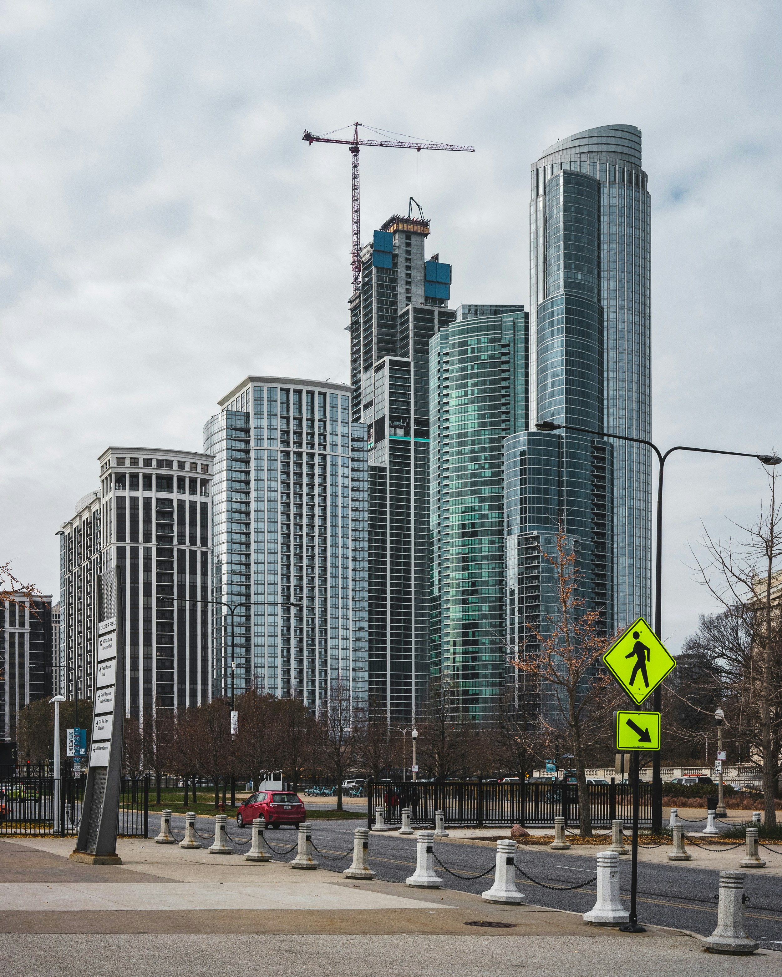 Crane-lit Glass: Towers Climb Above a Quiet City Street