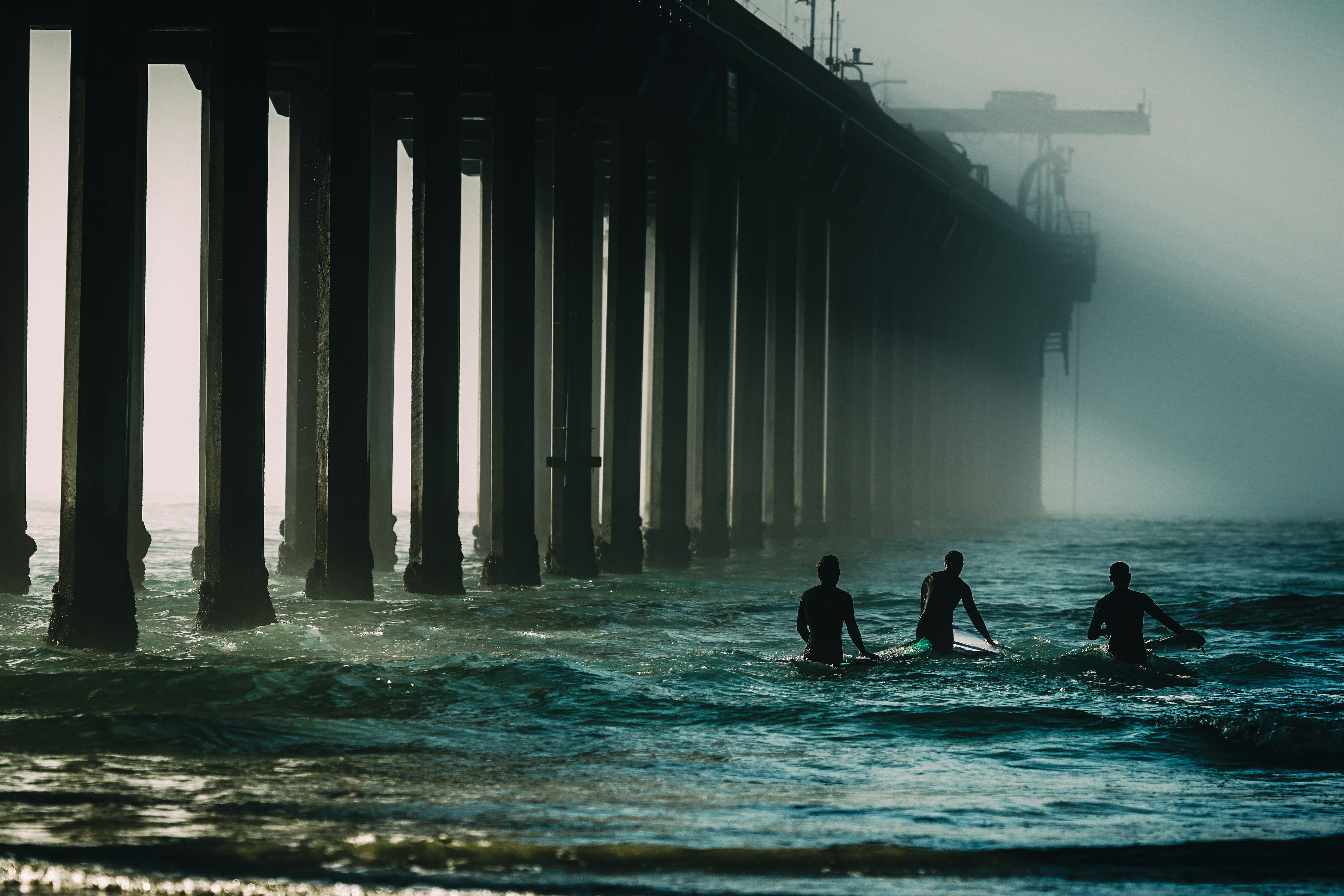three people in ocean near bridge