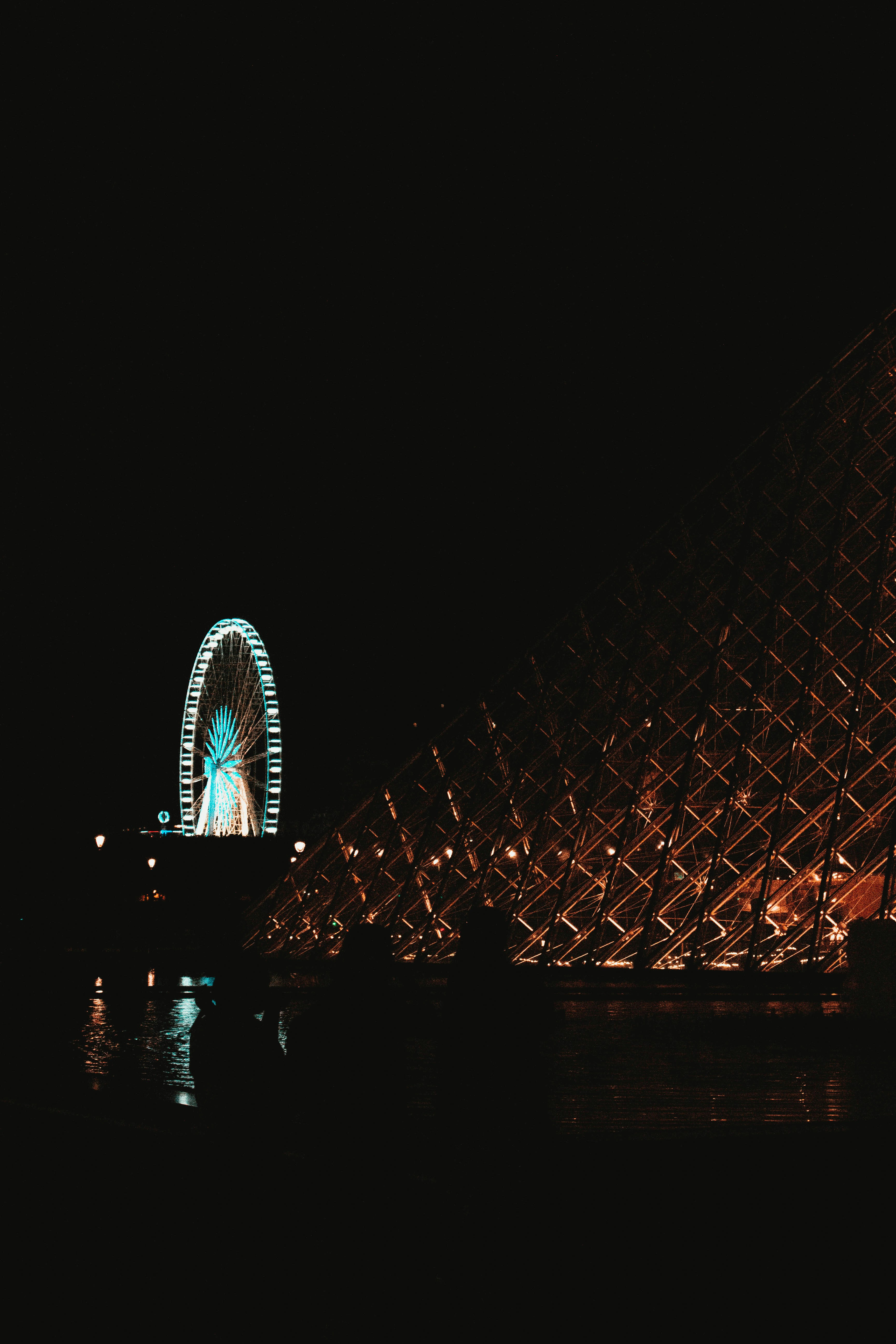 Nocturnal Ferris Wheel Echoes Across the Louvre Pyramid