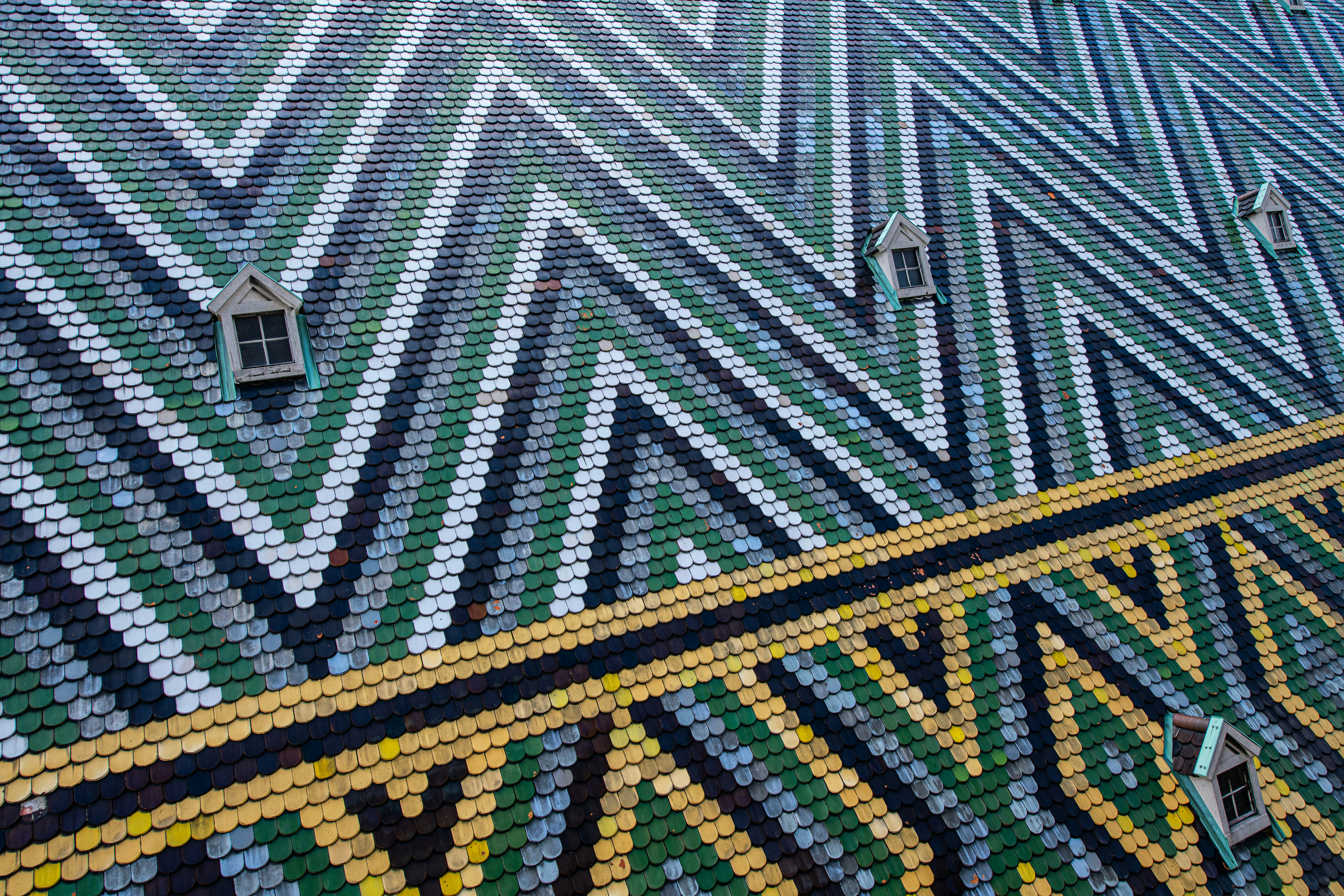 Chevron Quilt on a Roof: Emerald, Azure and Amber Tiles Framing Tiny Dormer Windows