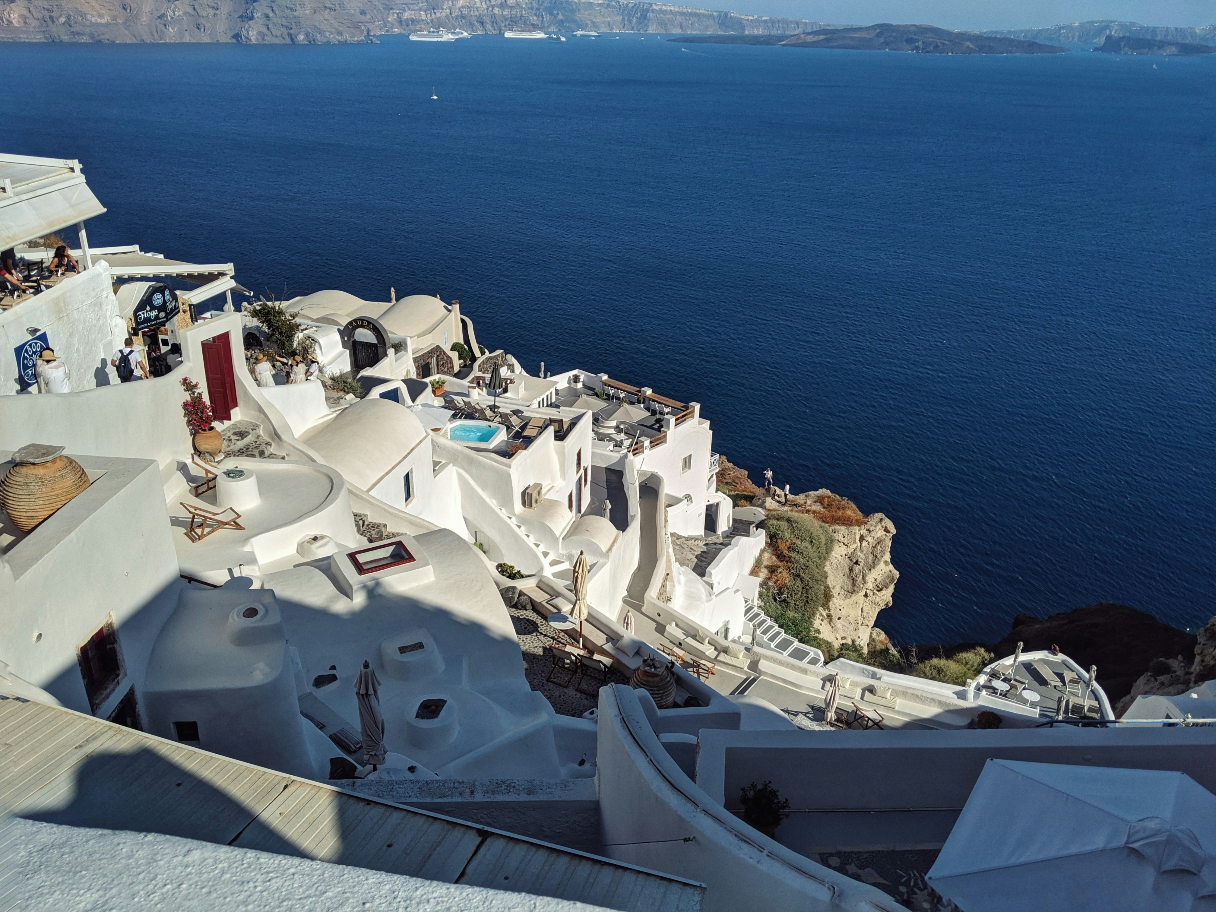 Whitewashed buildings cascade down a cliffside in Oia, Santorini, overlooking the deep blue Aegean Sea.