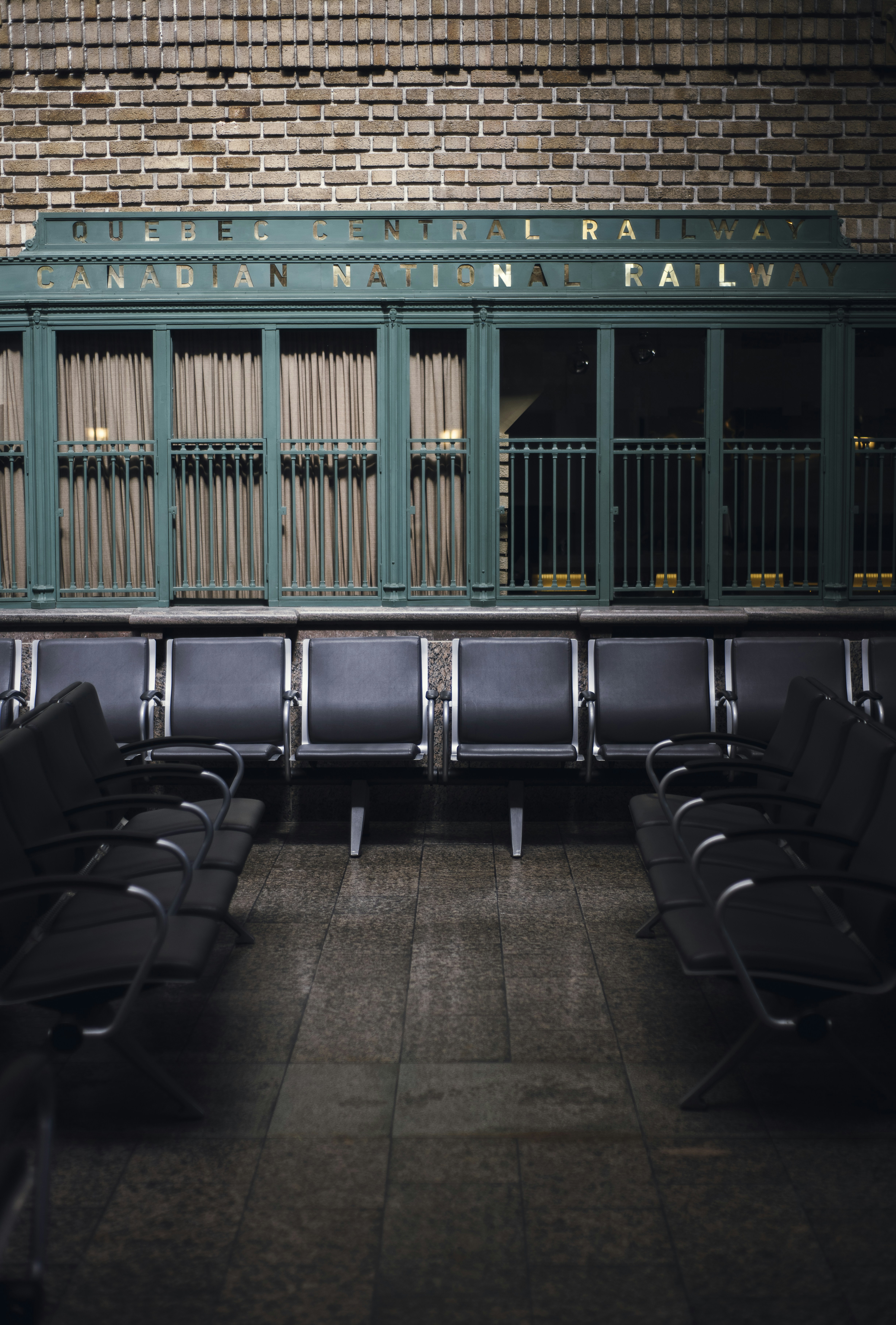 Historic railway station waiting area featuring elegant green accents and neatly arranged seating. The backdrop showcases the iconic Canadian National Railway signage.