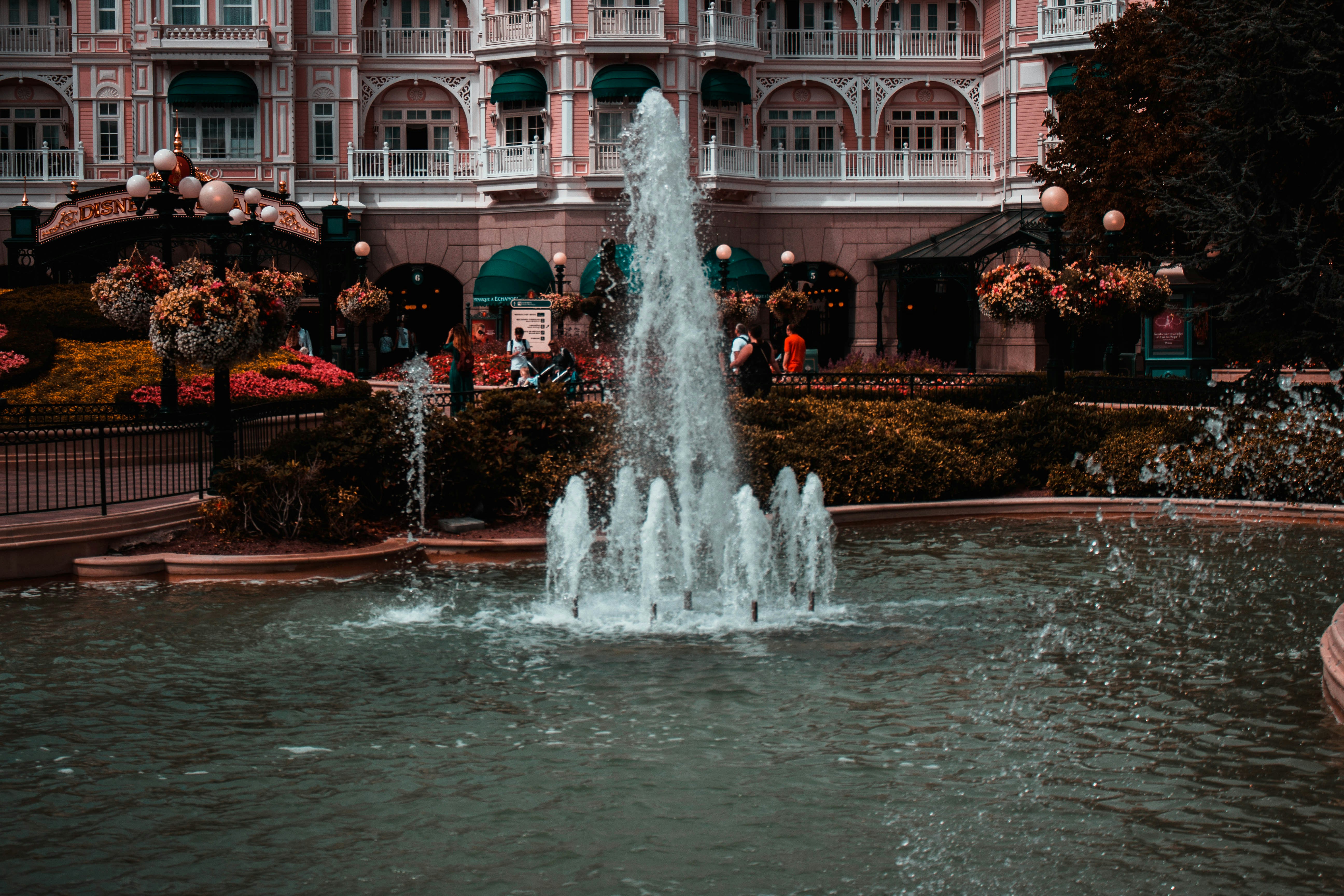 Fountain in a European-inspired plaza: stone arches, blossoms, and a central jet