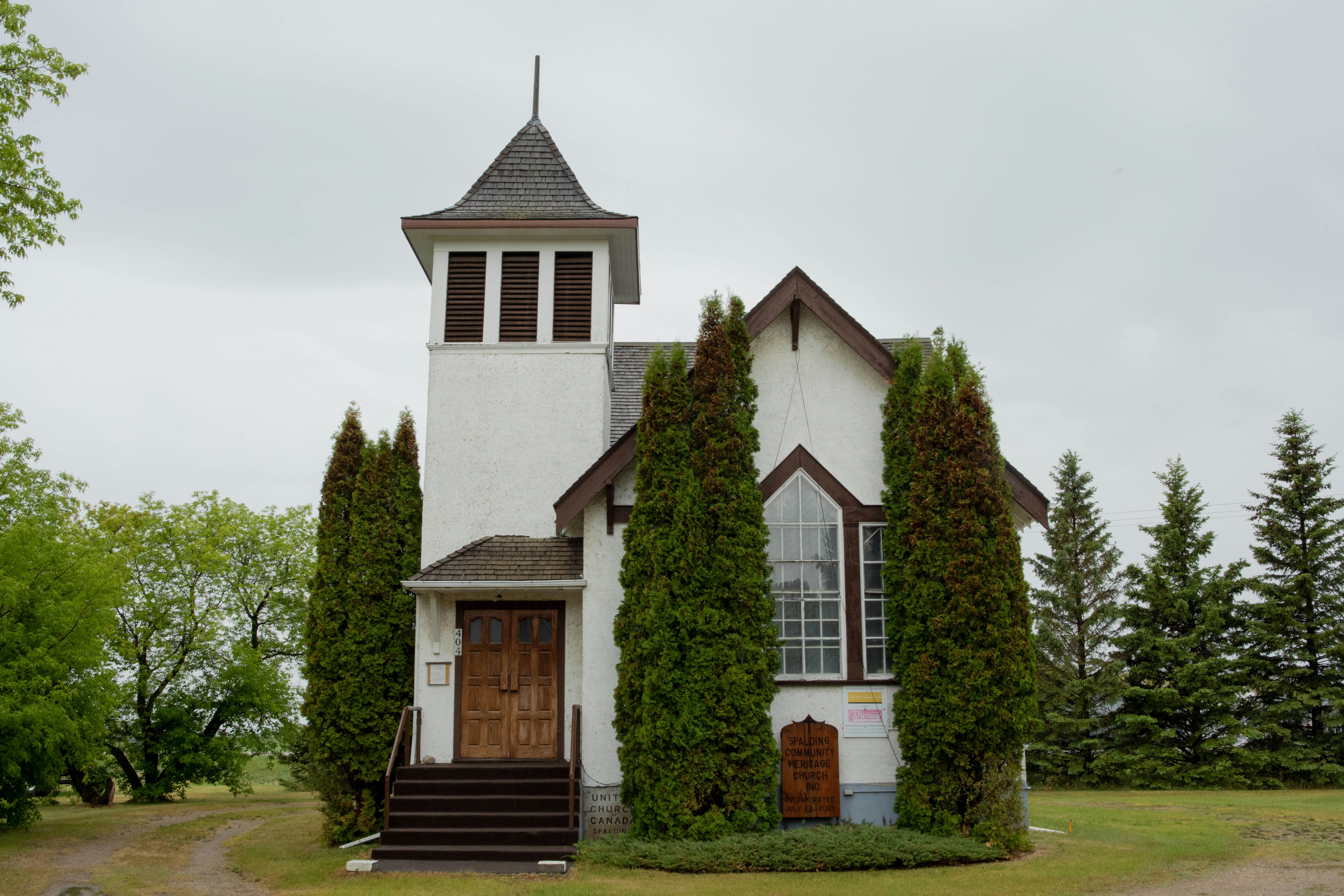 A quaint, weathered chapel surrounded by lush greenery, showcasing its unique architecture and charming details. The scene evokes a sense of nostalgia and tranquility.