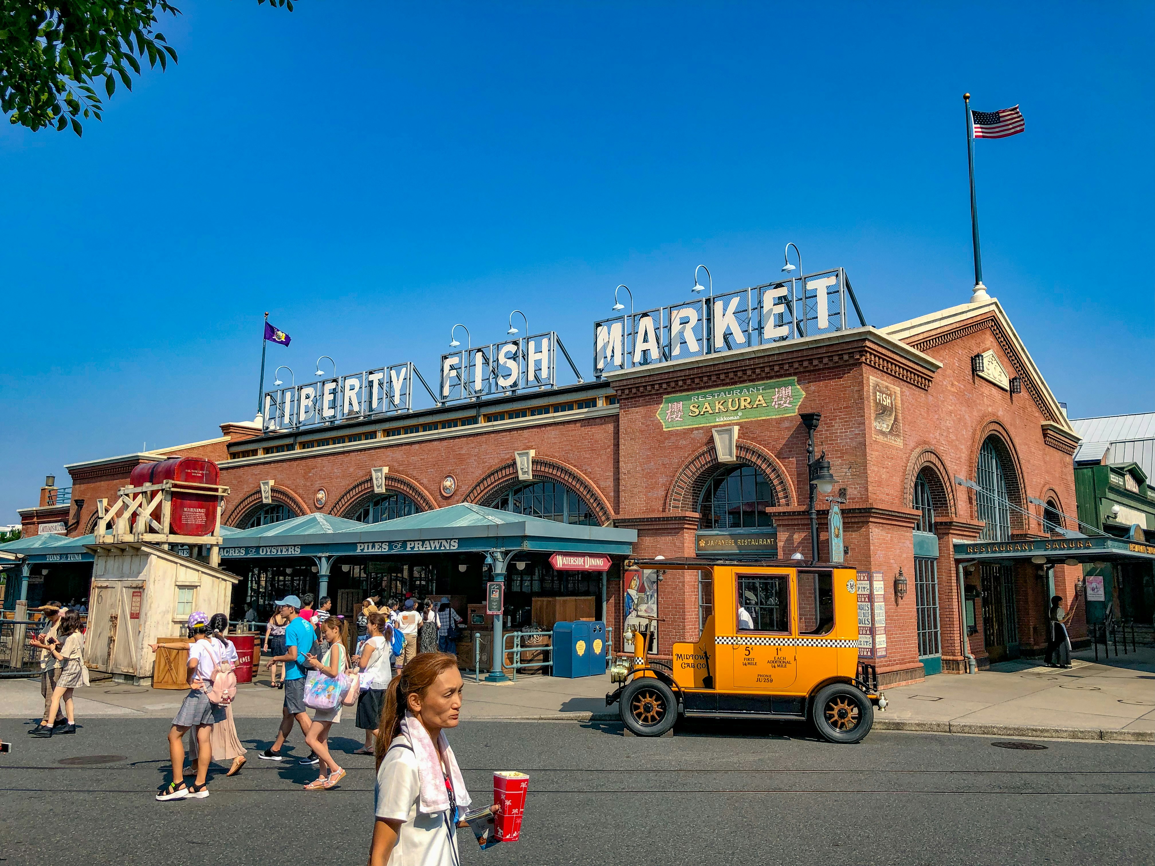 Historic Liberty Fish Market bustling with visitors and vendors under a clear blue sky. The iconic signage adds charm to the vibrant atmosphere.