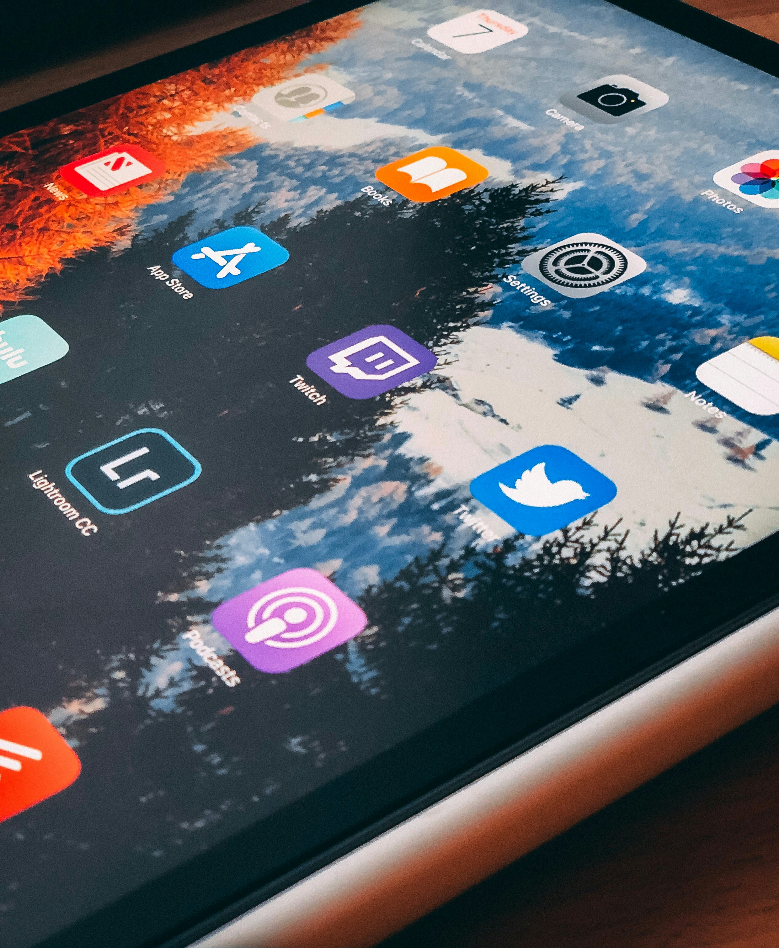 Tablet screen displaying app icons with a scenic mountain wallpaper.