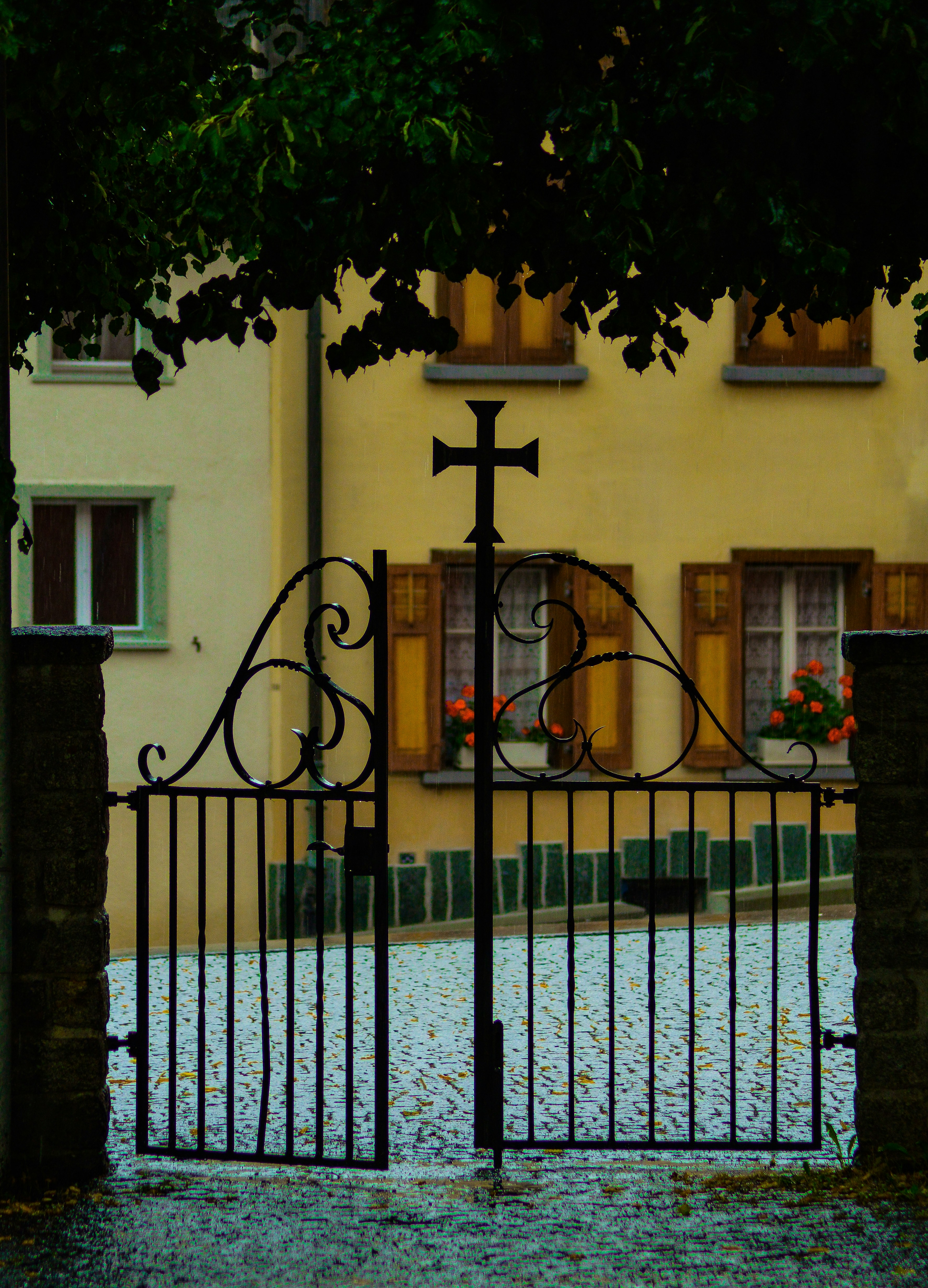 Cross-Topped Gate Framing a Sunlit European Courtyard