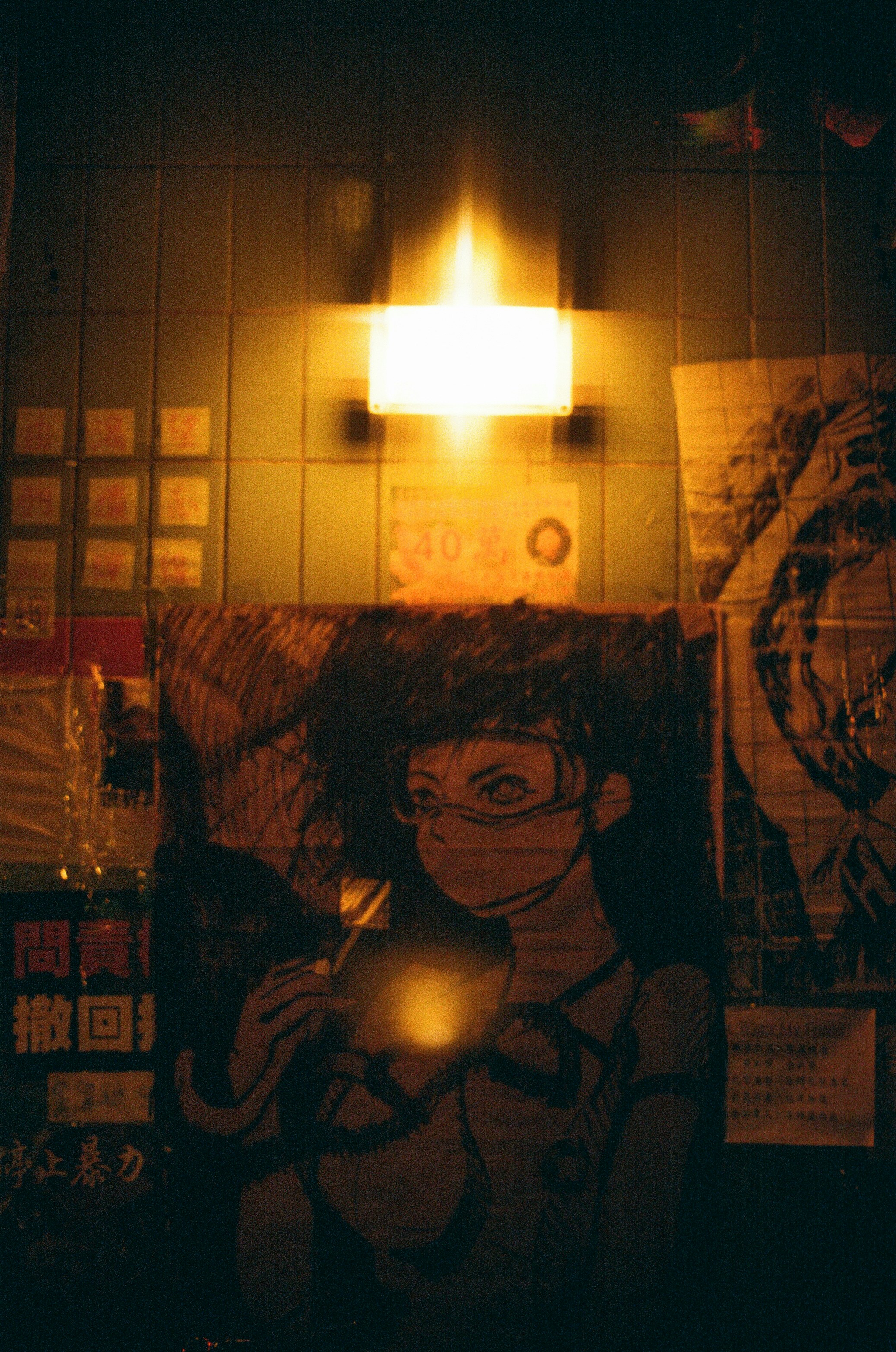 Dimly lit wall features an illustrated poster of a masked figure beneath a warm, square ceiling light, surrounded by other posters and tiled panels. The scene evokes an intimate urban interior with a retro vibe.