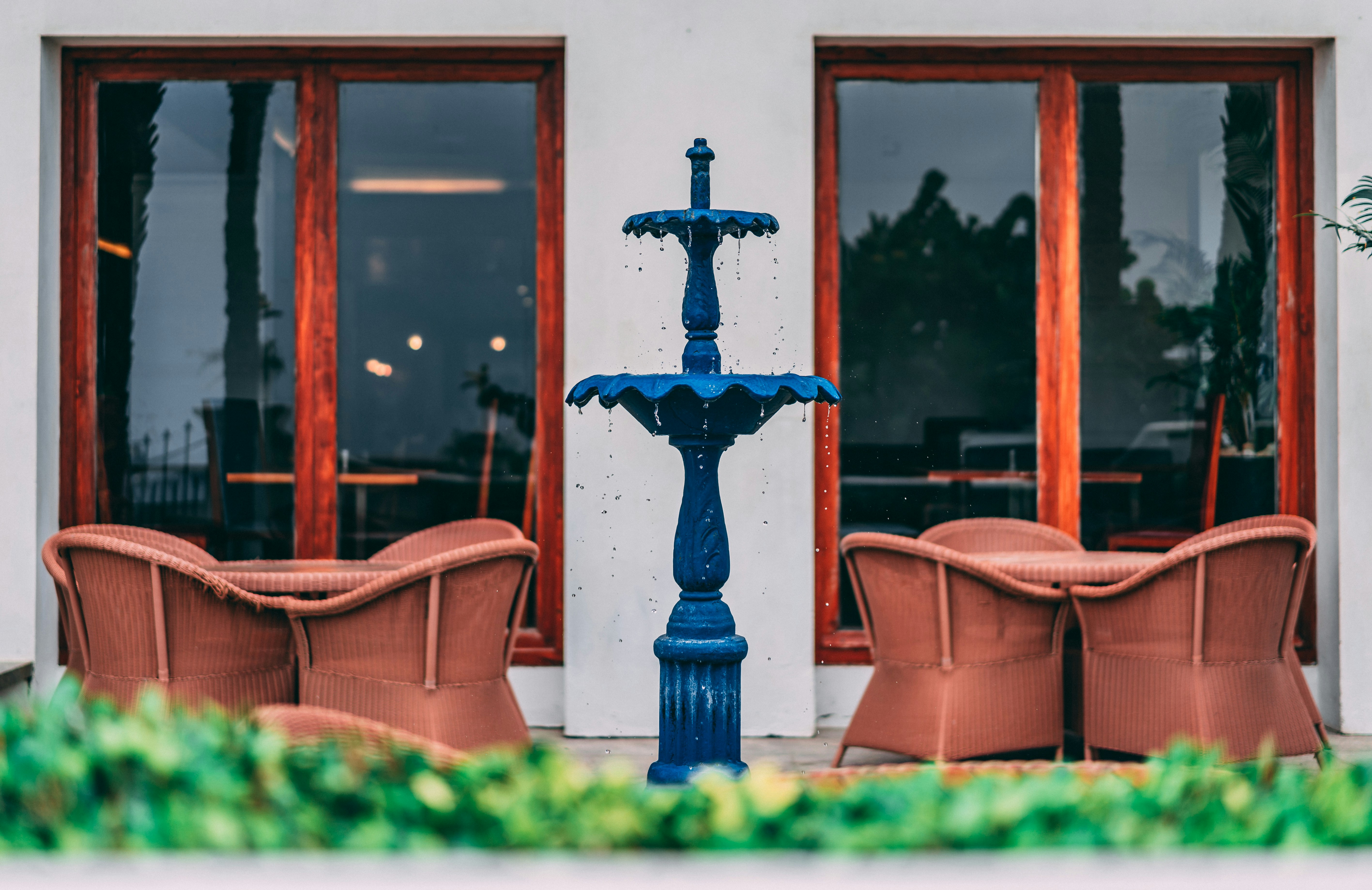 Cerulean Fountain Framed by Wicker Chairs on a Quiet Patio