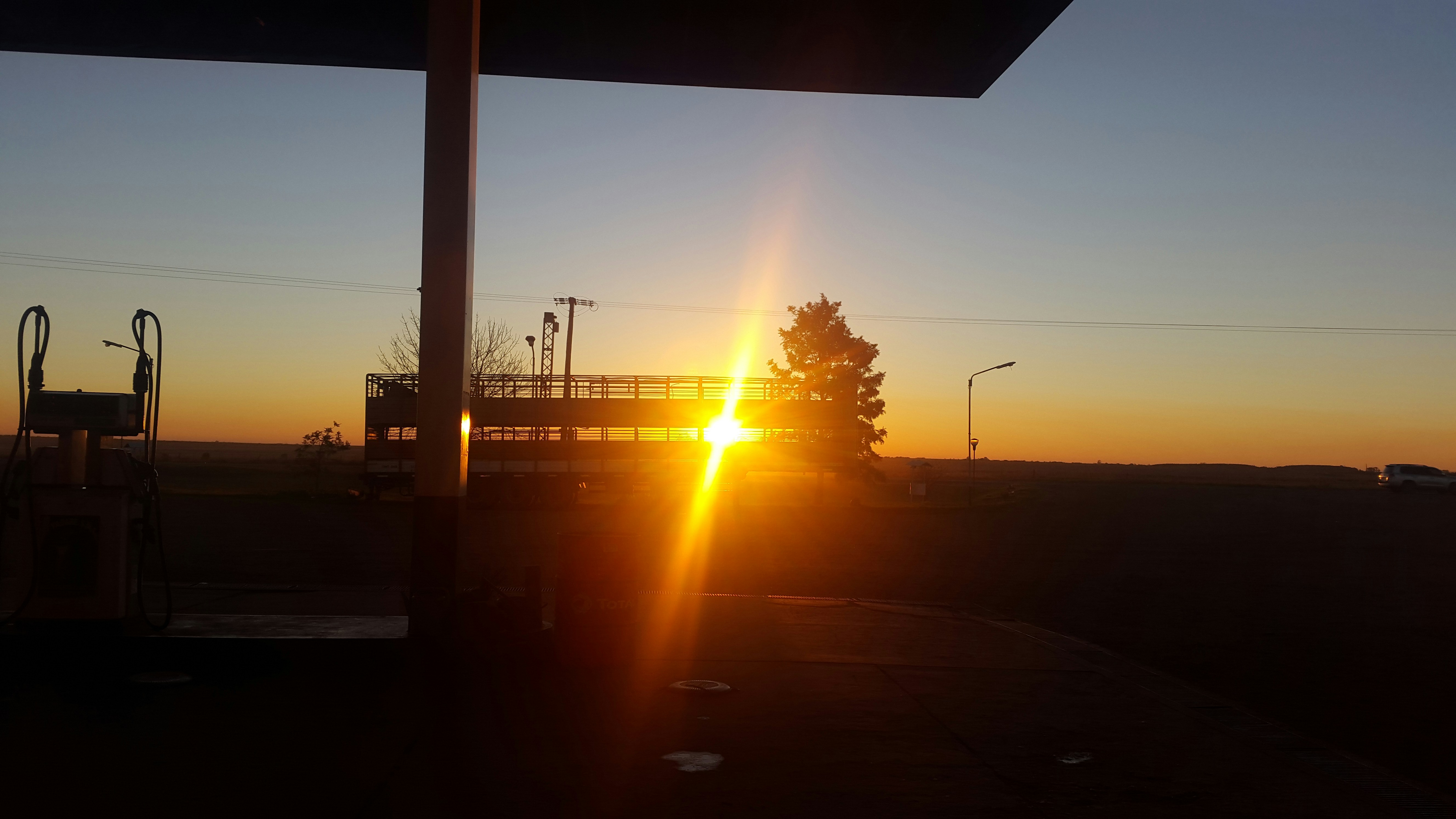 Sunburst Over a Quiet Service Station at Dusk