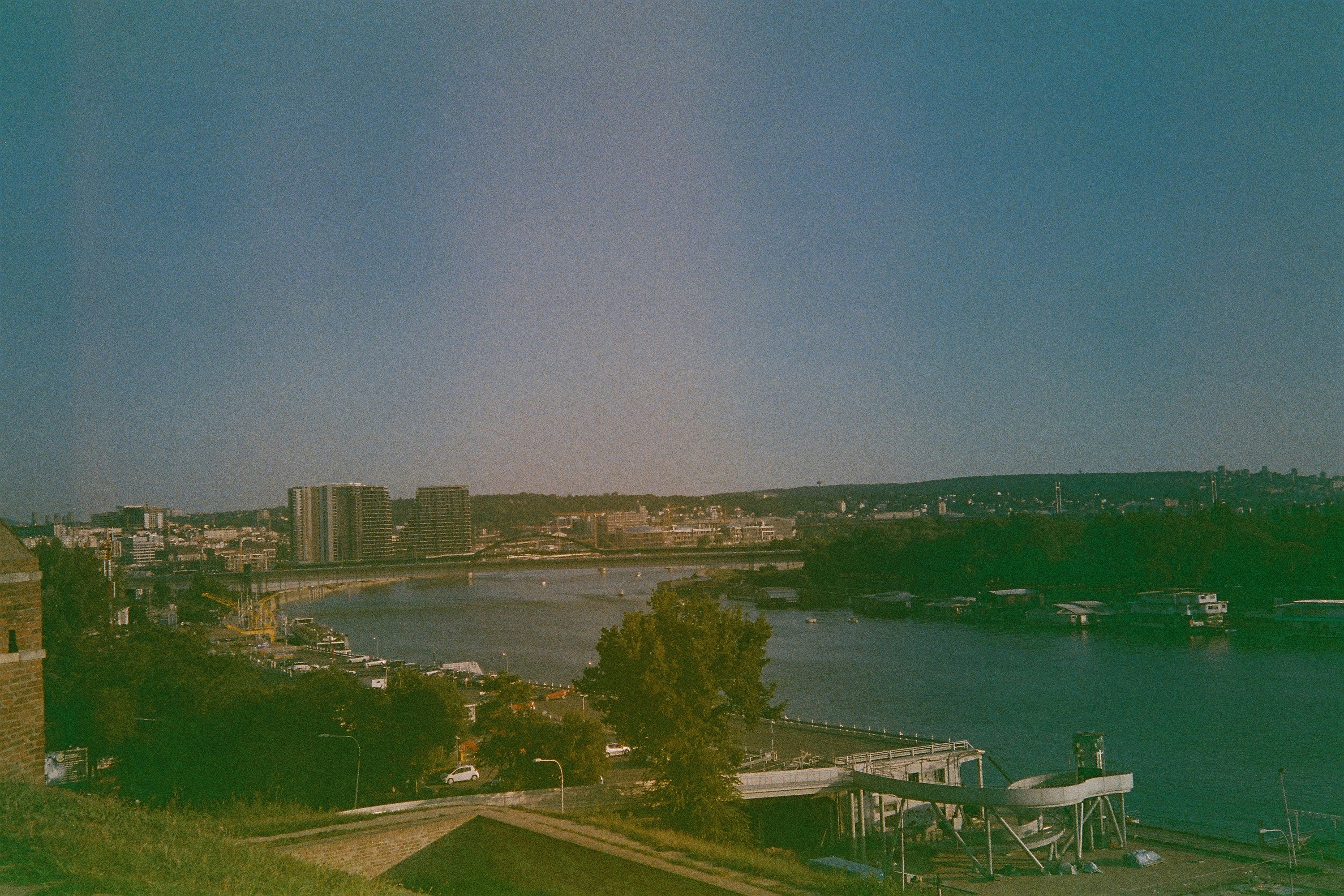 River winding between two cityscapes under a clear blue sky.