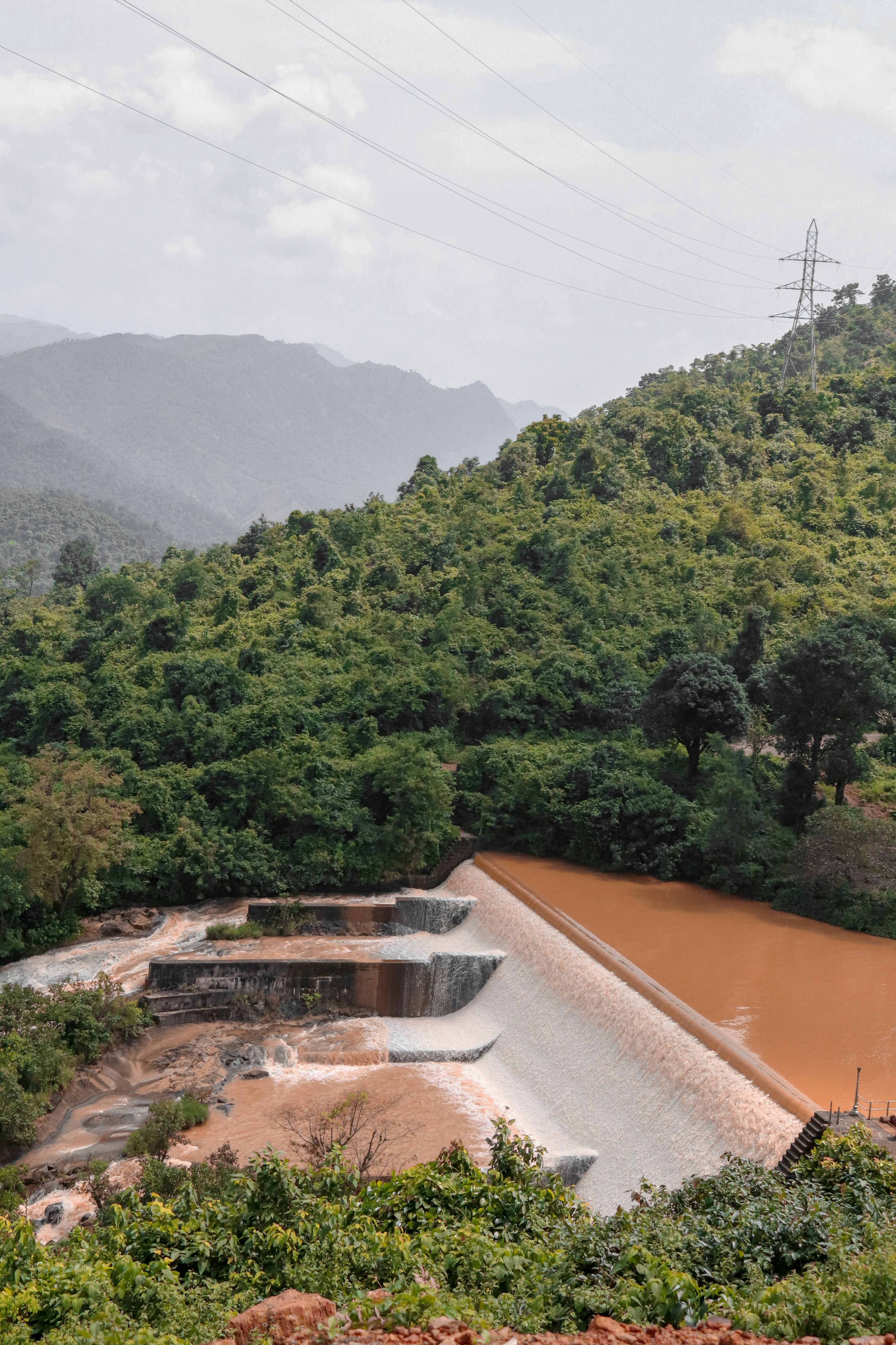 Terraced Spillway Carved by Rust-Colored River Through a Lush Hillside
