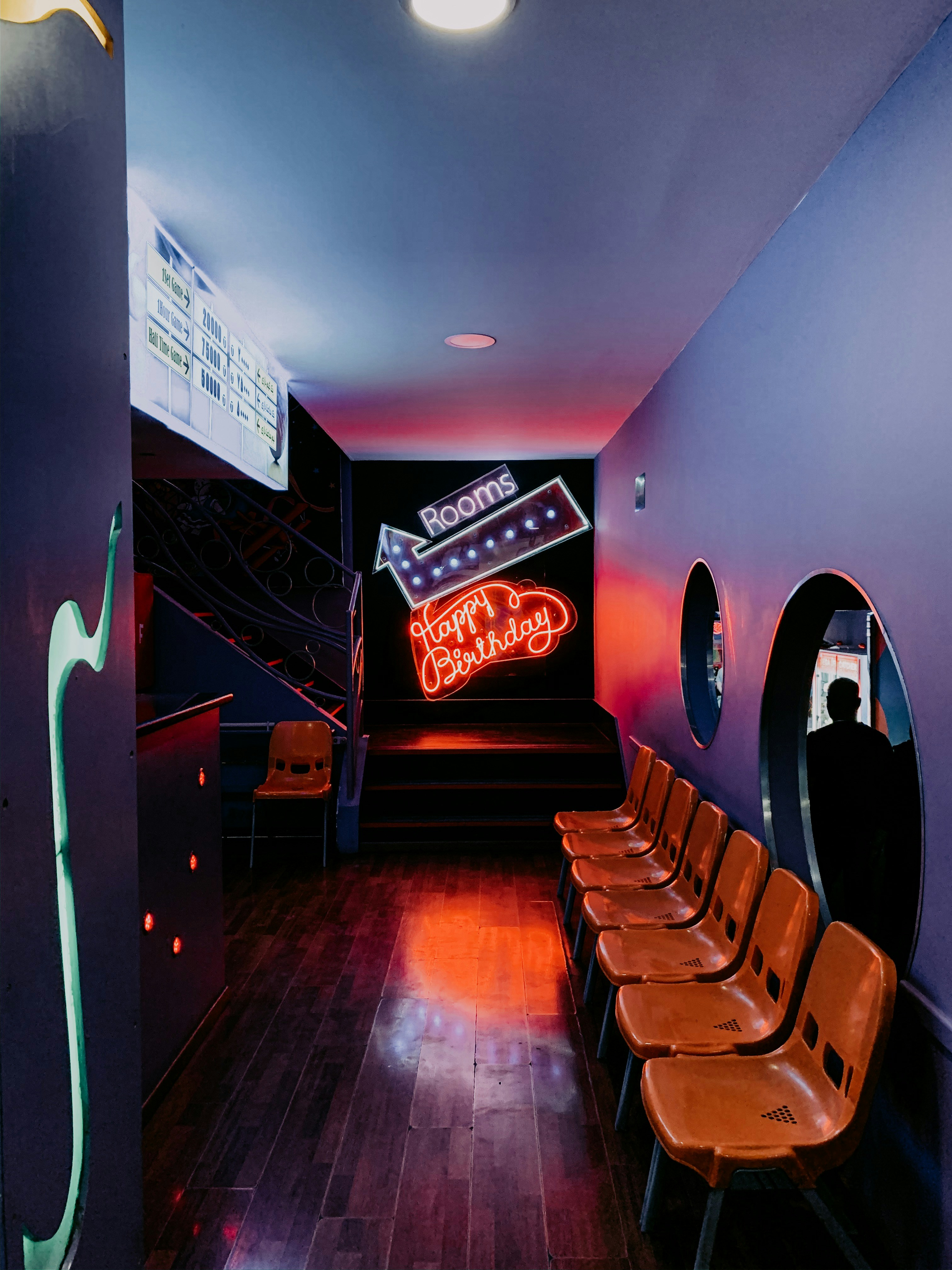 Red Birthday Neon Illuminates a Blue Hallway with Orange Seats