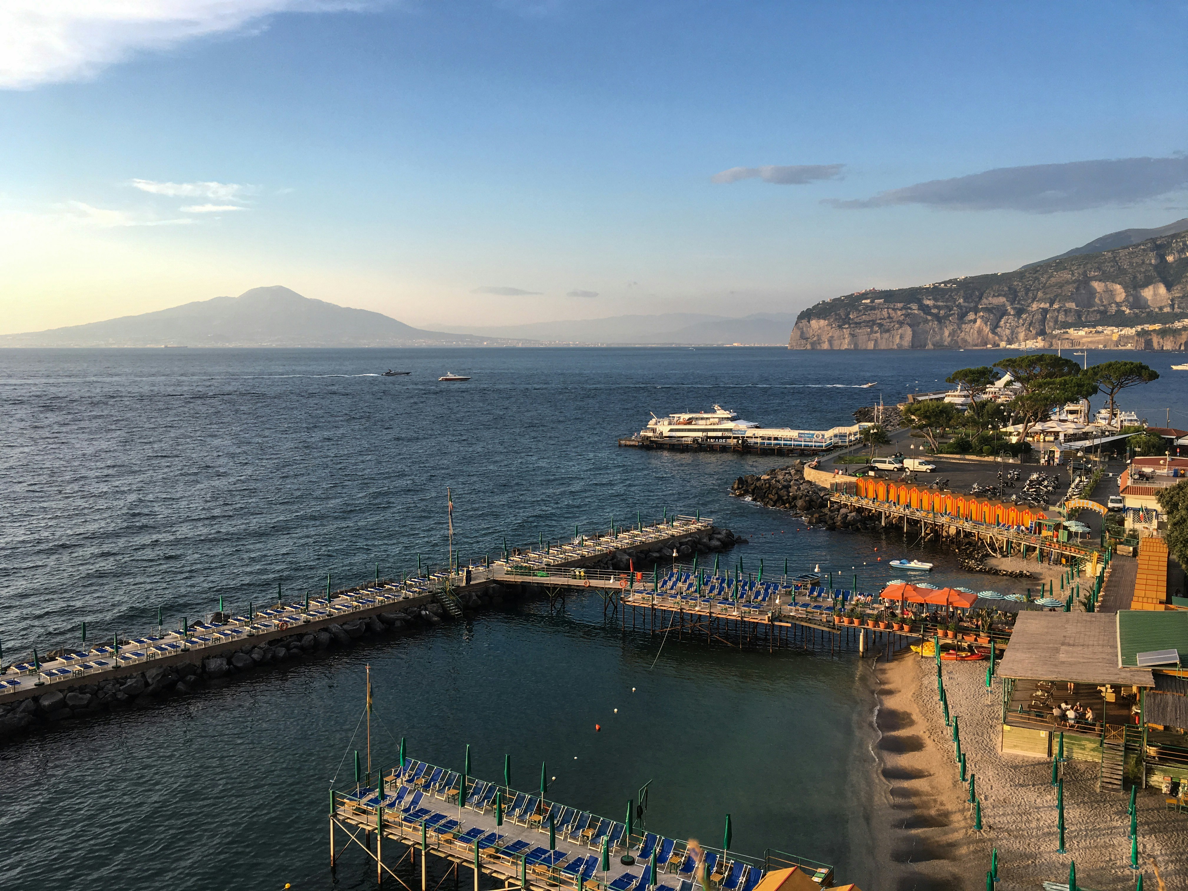 Promenade of Blue Chairs: A Sunlit Harbor Framed by Cliffs