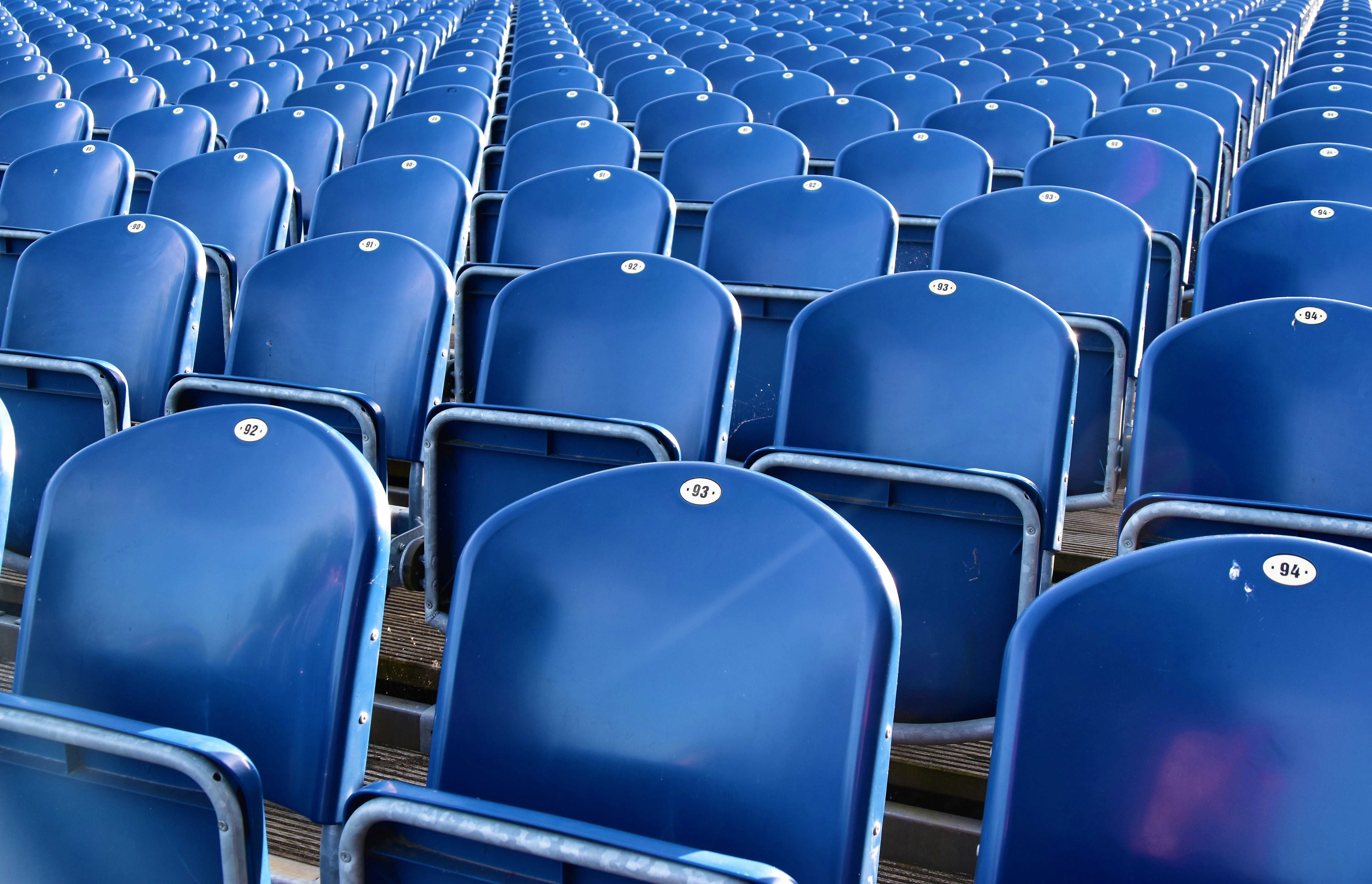 A vast arrangement of blue stadium seats, each numbered, creating a rhythmic pattern that evokes the excitement of upcoming events.