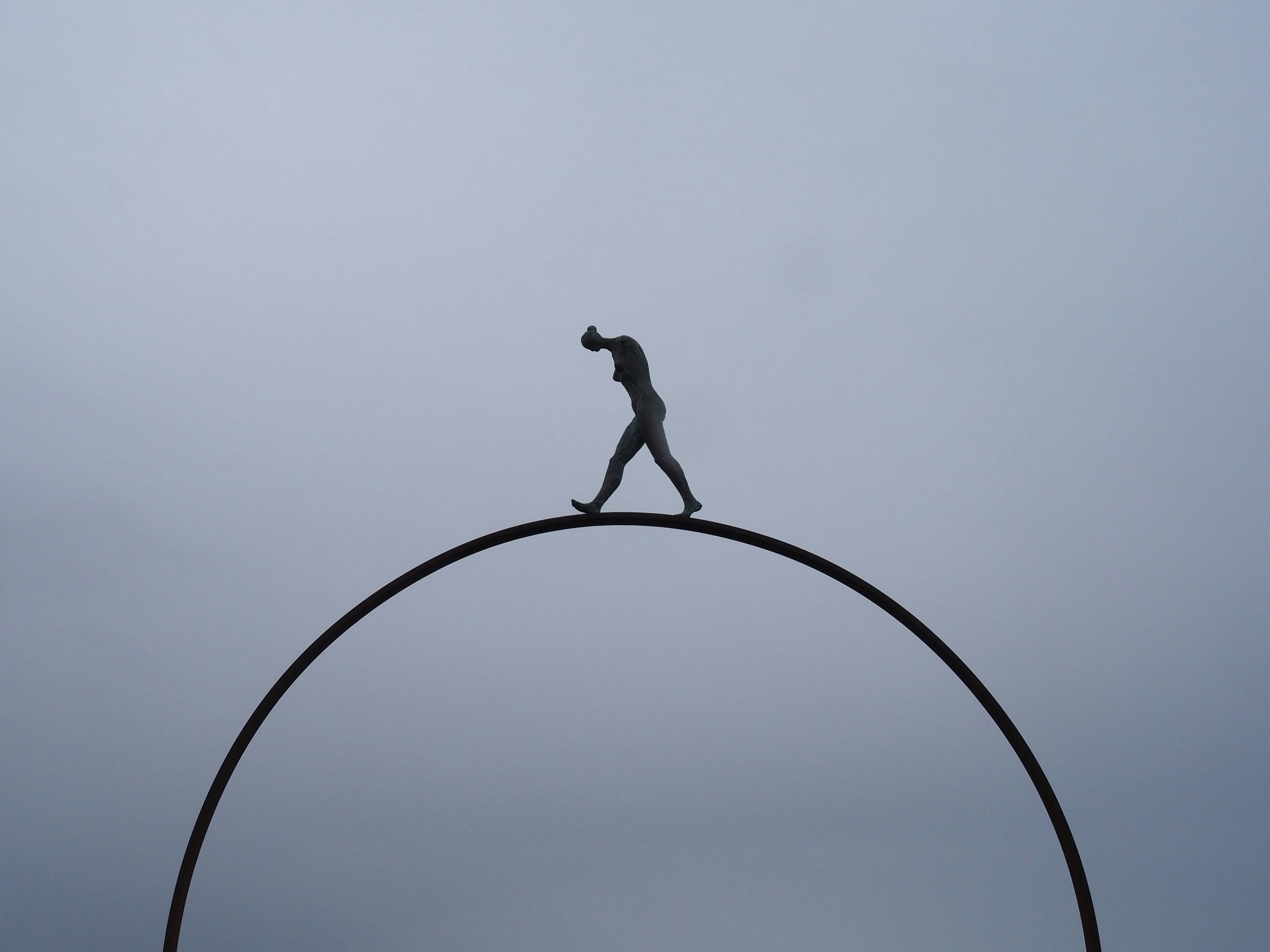 On the Ring: A Silhouette Traverses the Circular Arch Against a Cloudy Sky
