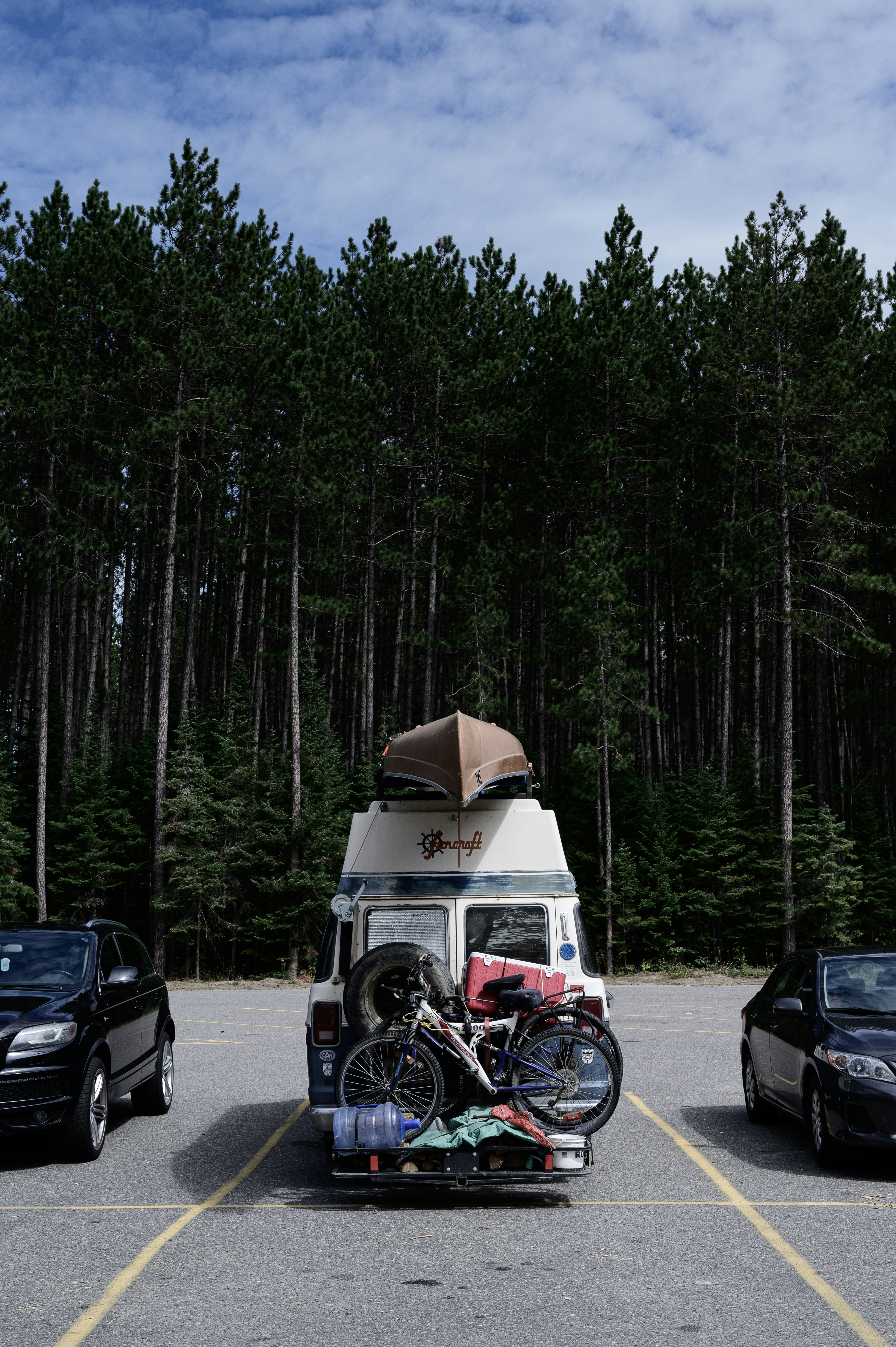 Roof-Top Tent Meets Two Bicycles: A Vintage Camper in a Pines-Lined Parking Lot