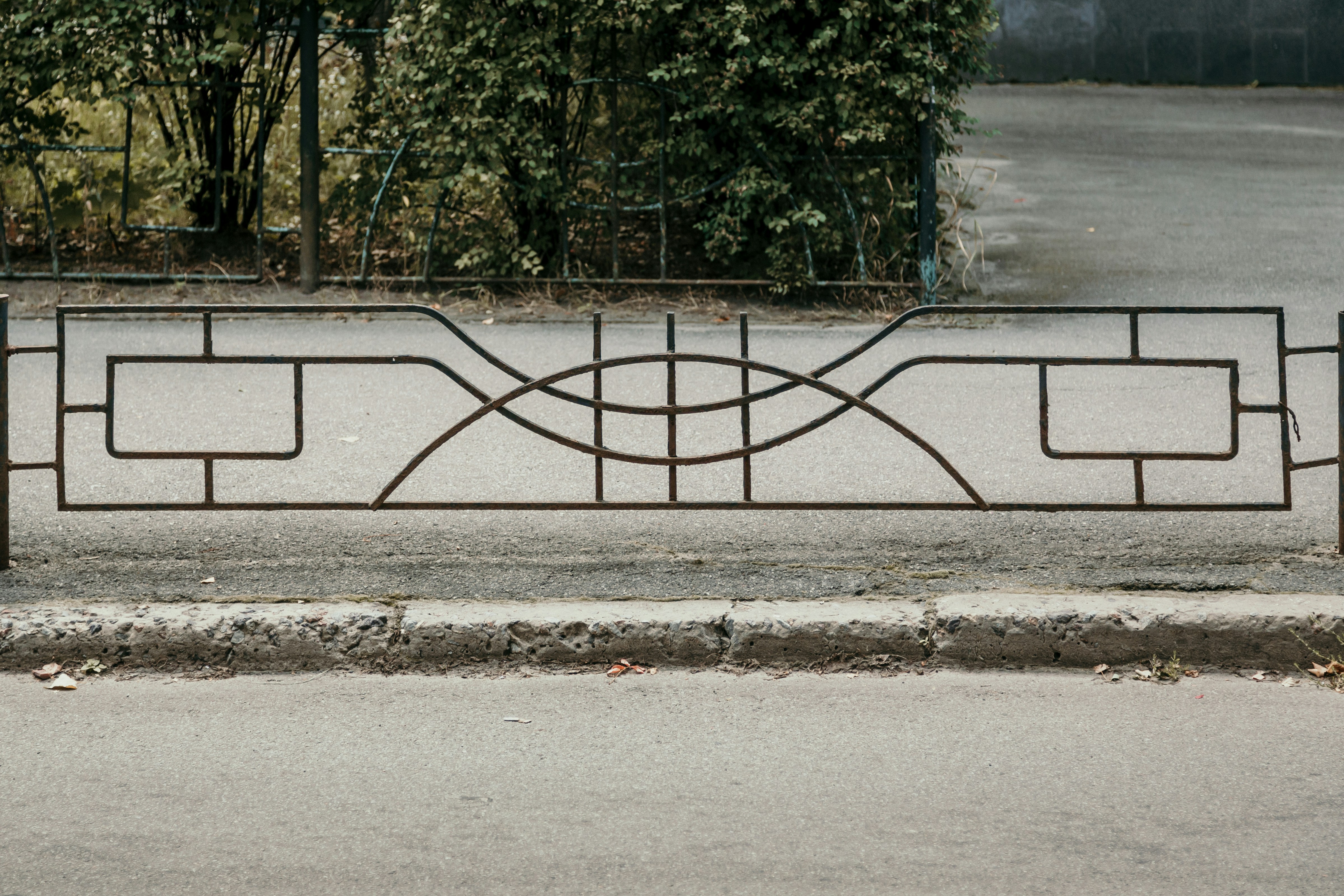Intricate iron railing design with geometric patterns set against a muted urban backdrop.