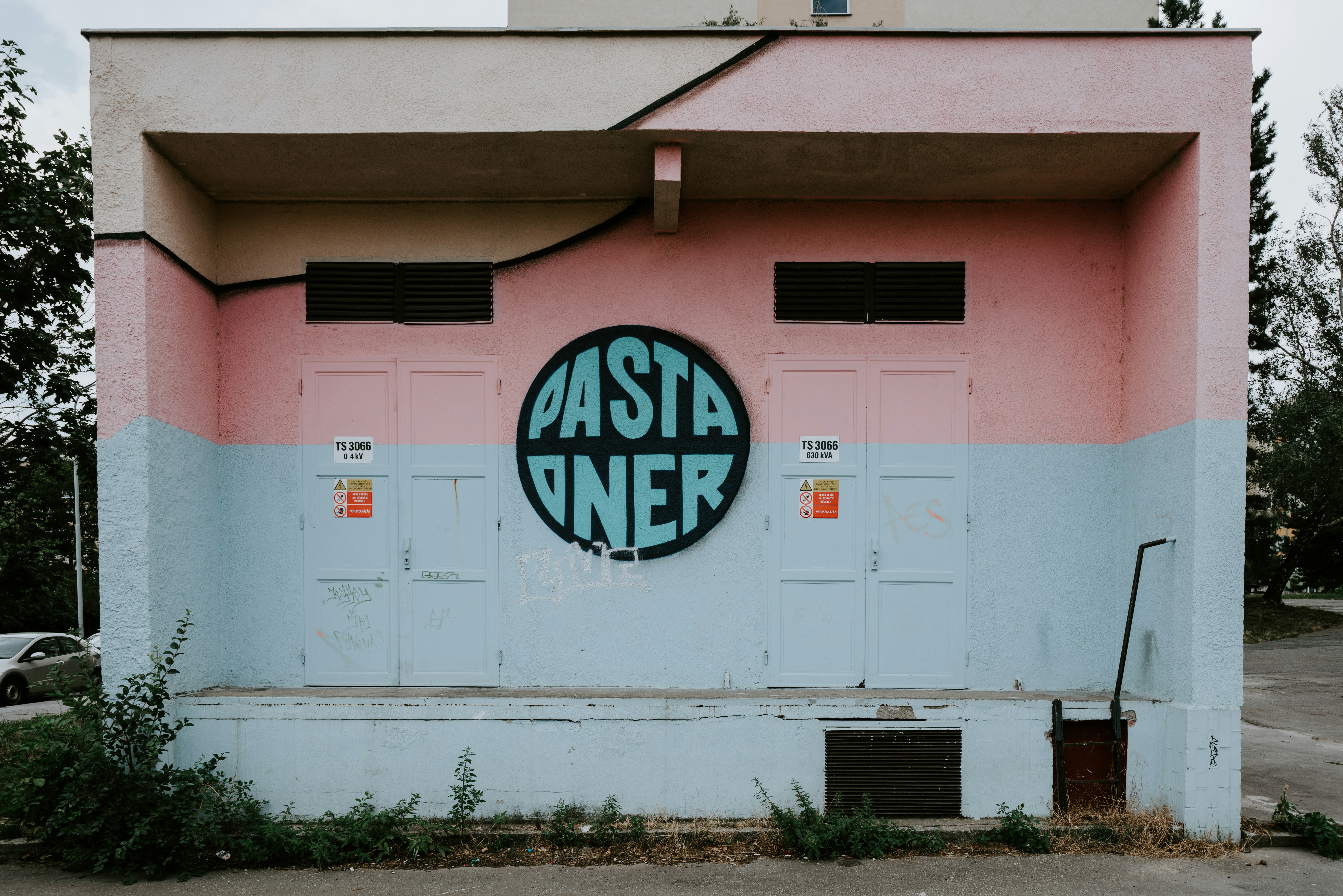 Vibrant mural featuring the word 'PASTA' on a pastel-colored wall, capturing the essence of a food establishment. The design contrasts with the surrounding architecture.